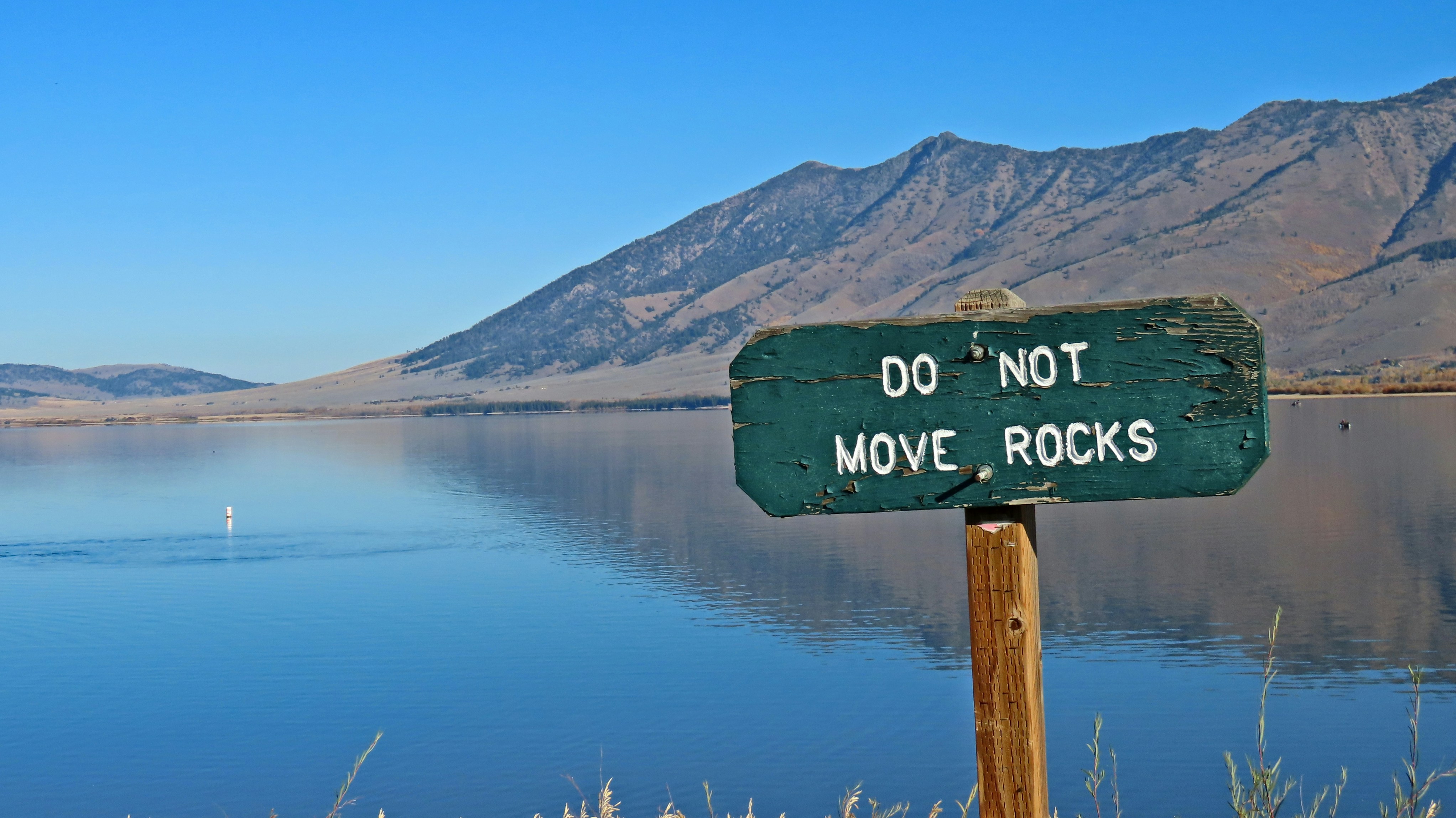 Signpost at the Edge: Do Not Move Rocks Over a Mirror Lake