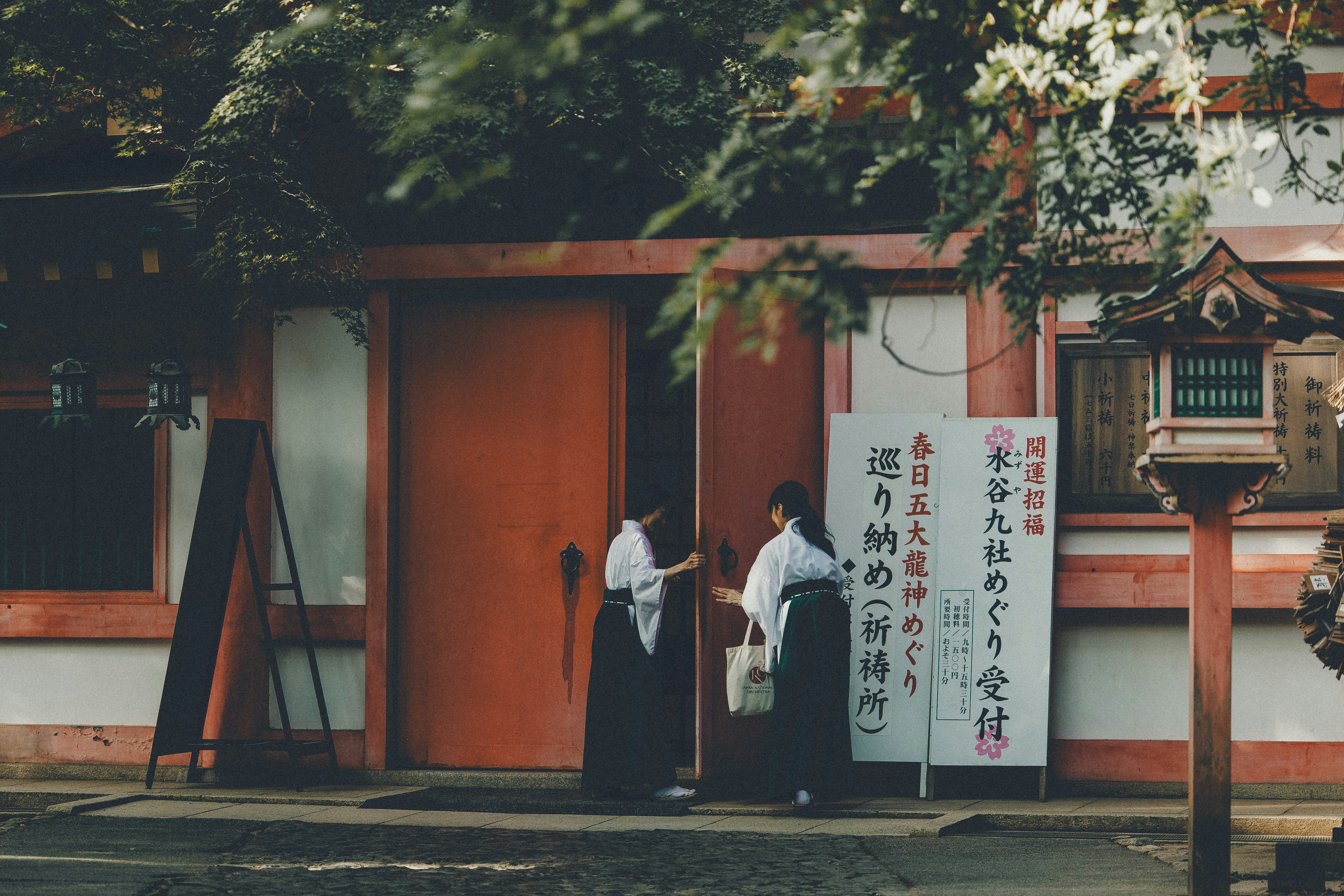 Suspended in Passage: Two Visitors at a Traditional Japanese Shrine Gate