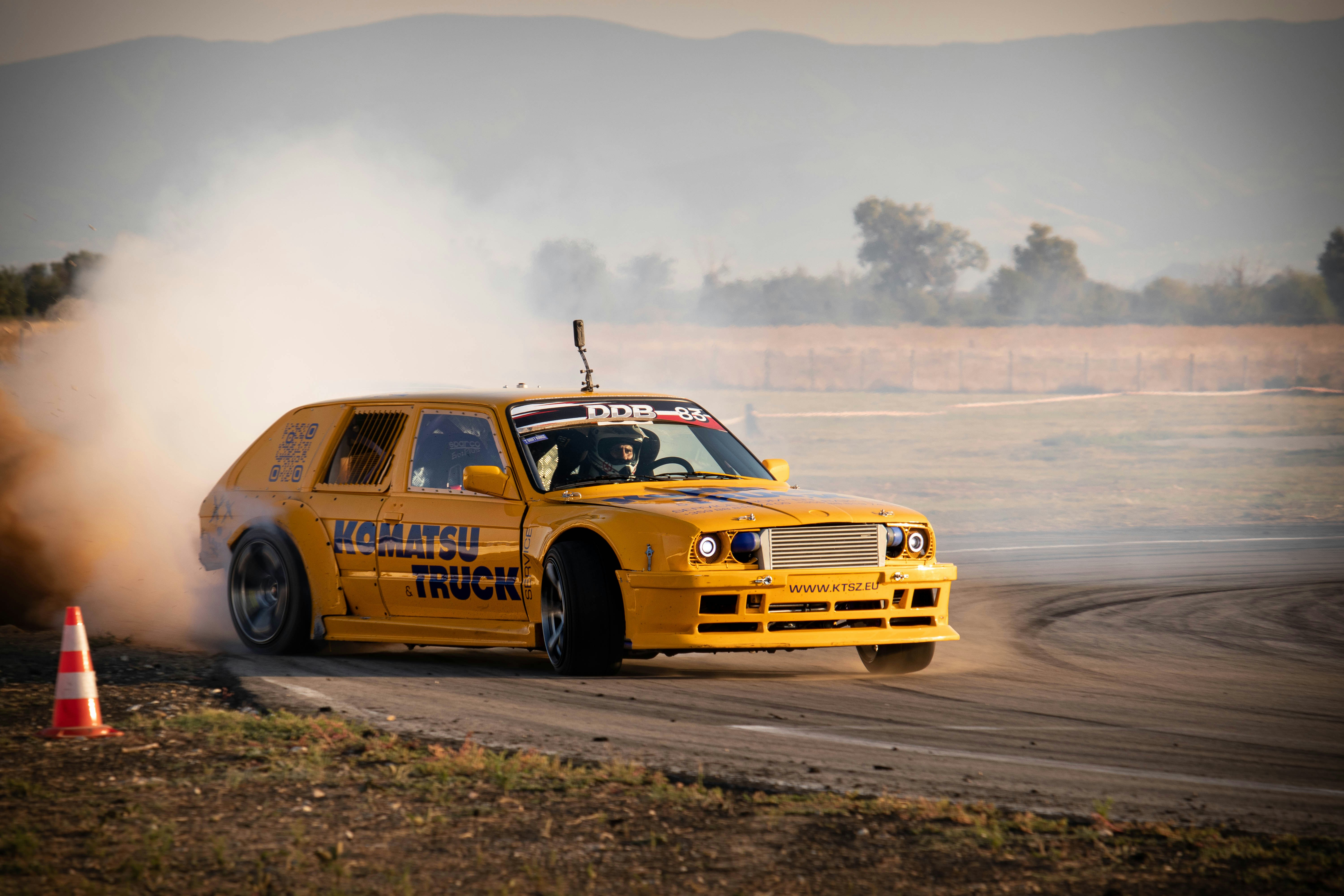 Yellow Drifting Sedan Erupts Smoke on a Curved Track