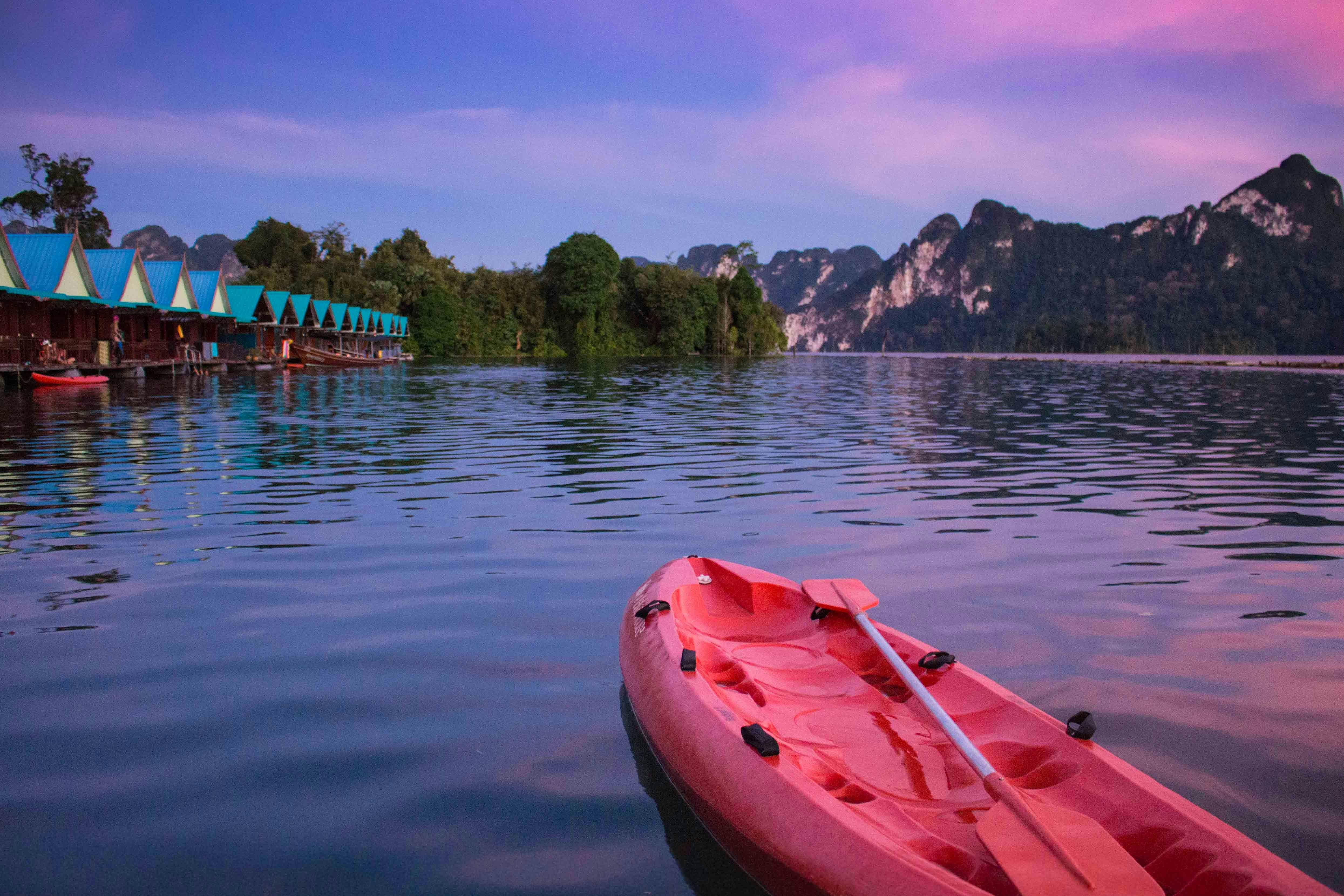 Pink Kayak at Dawn: A Serene Lake Scene with Mountain Backdrop