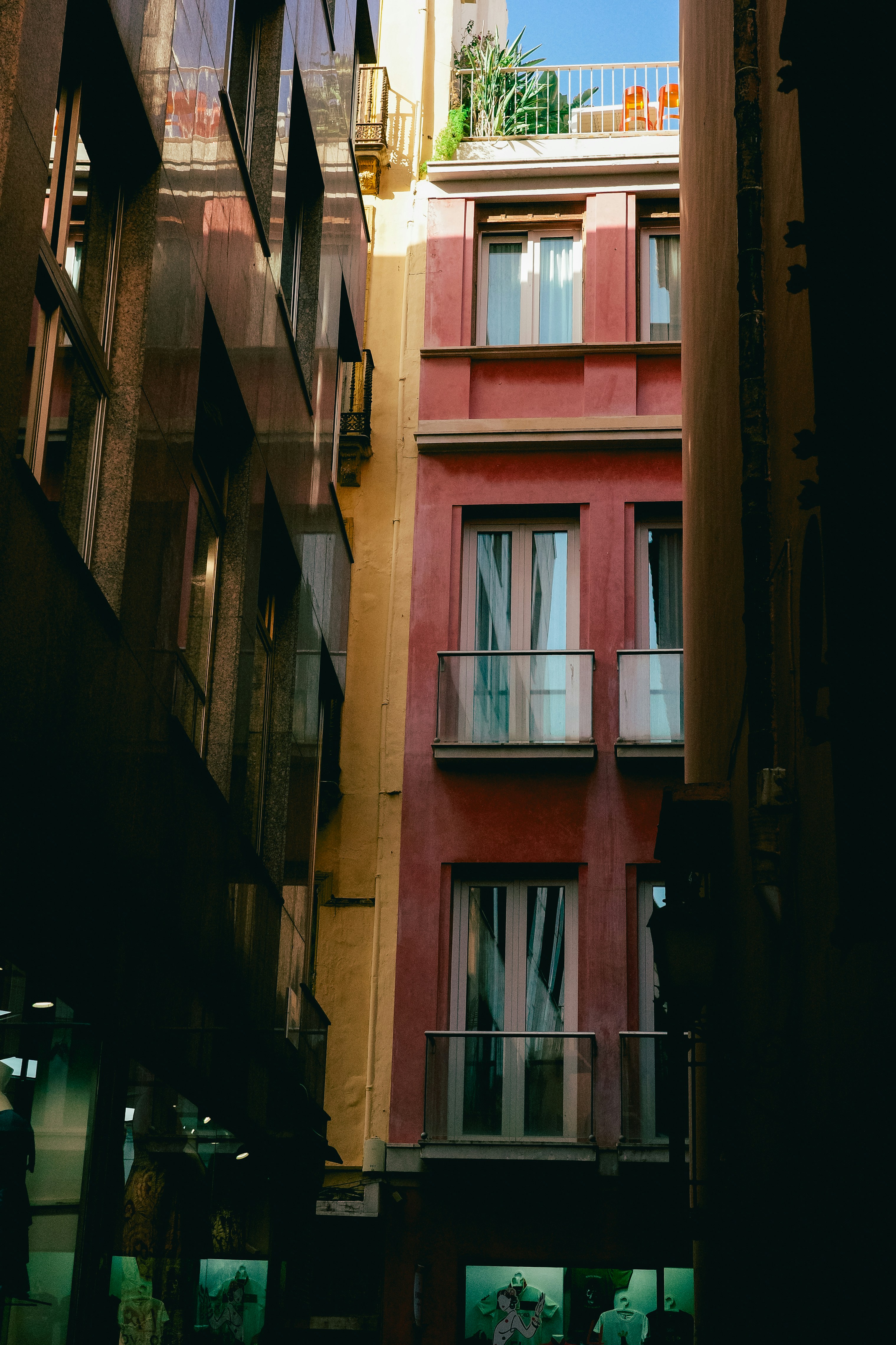 Colorful courtyard ascent: sunlit pink facade peeks through a narrow alley