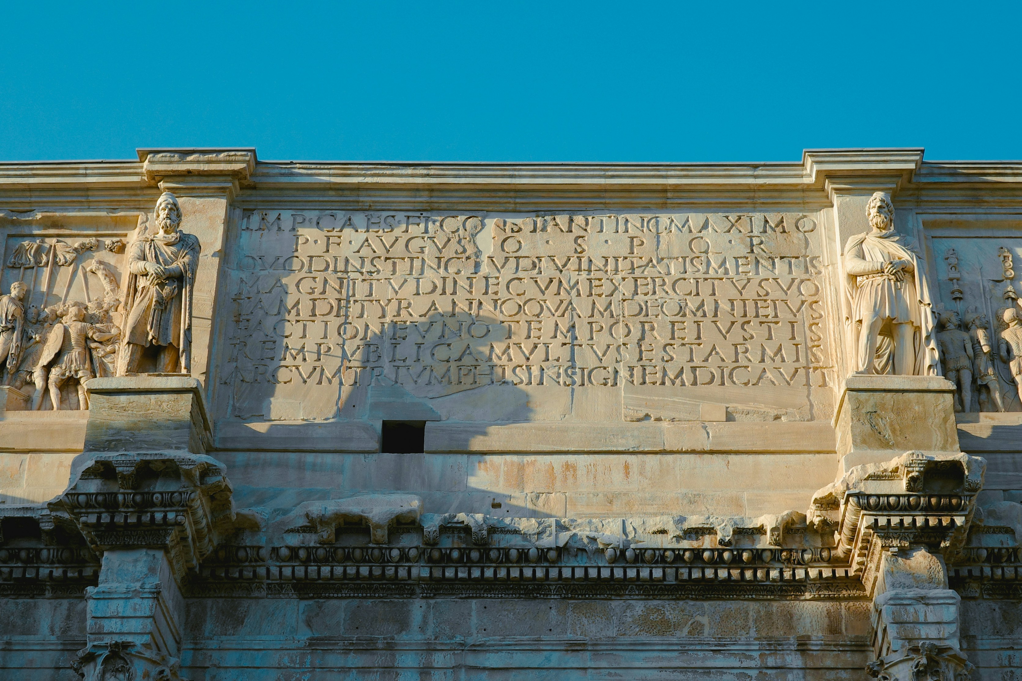 The Arch of Constantine with carved Latin inscriptions and stone statues in Rome