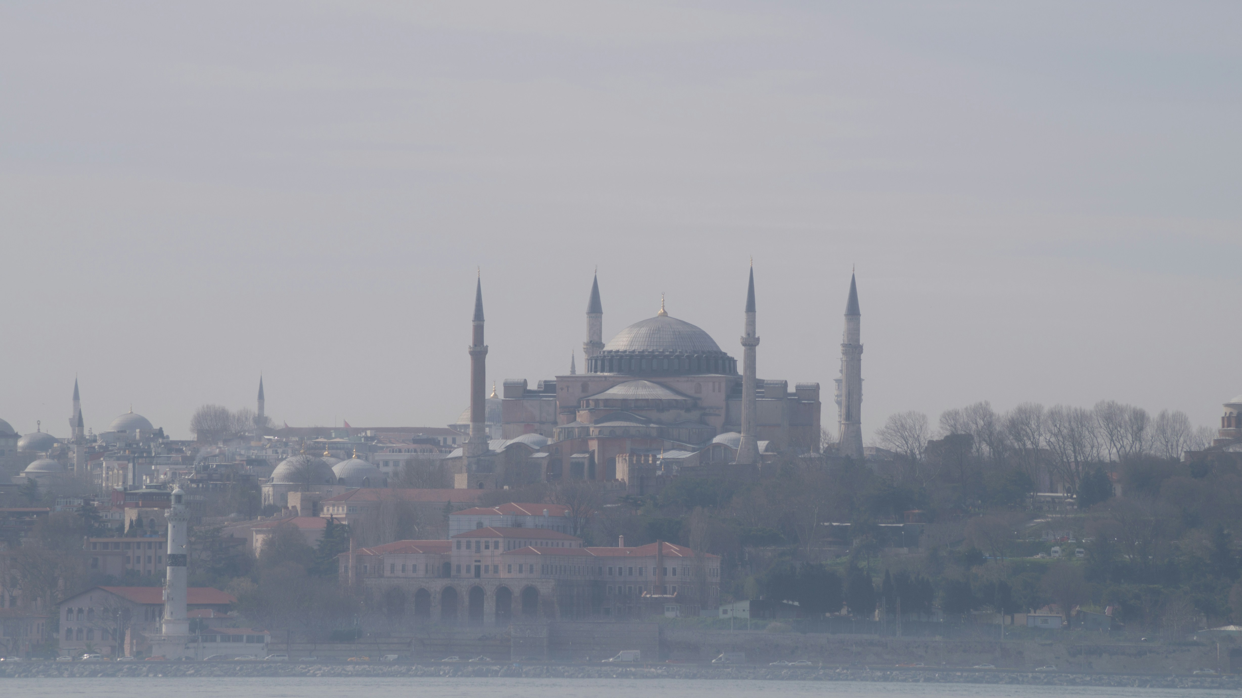 Hagia Sophia silhouette shrouded in coastal haze above the waterline, with minarets detailing the skyline.