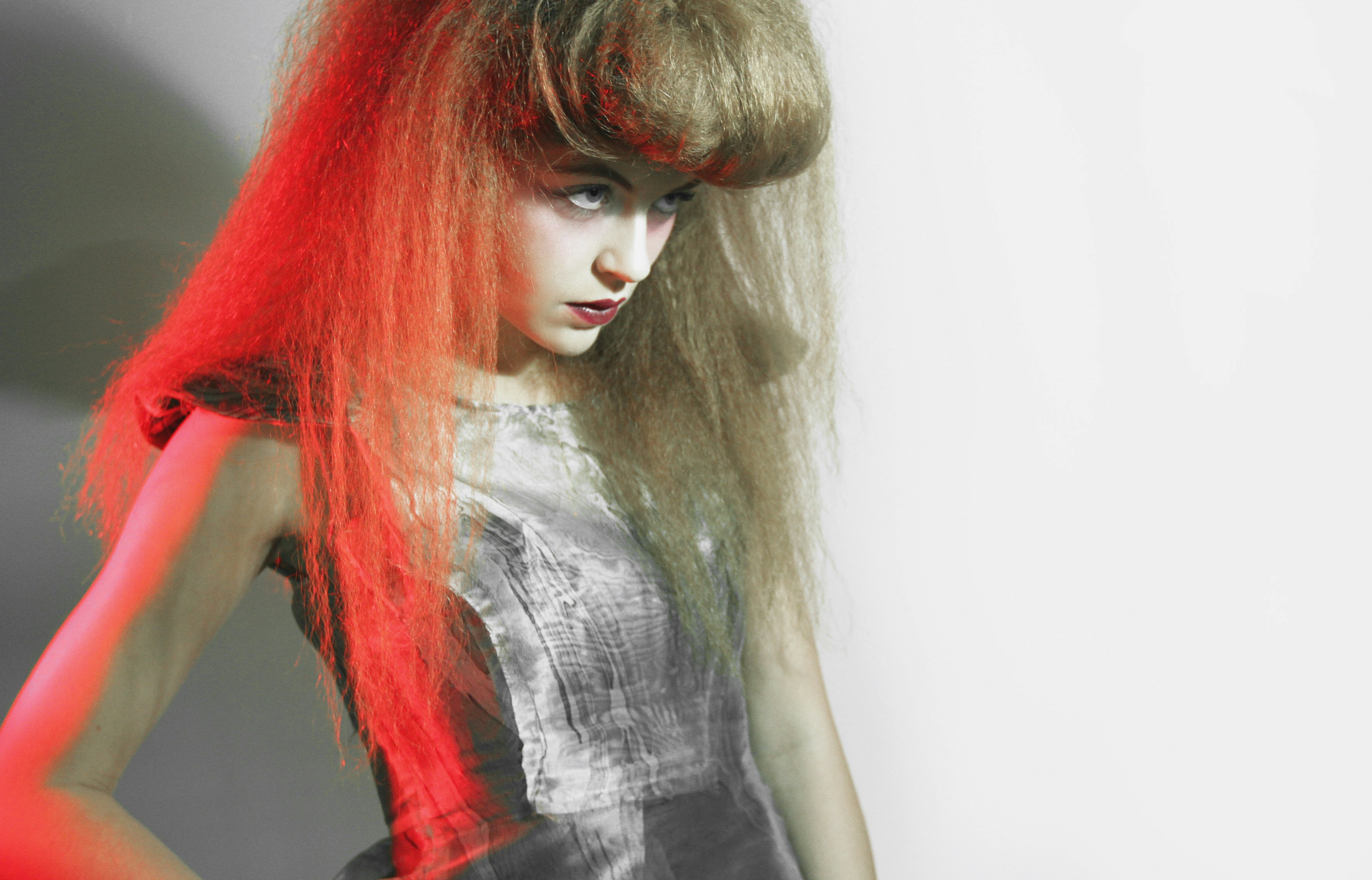 Crimson fringe and pale gaze: a fashion portrait in high-contrast light