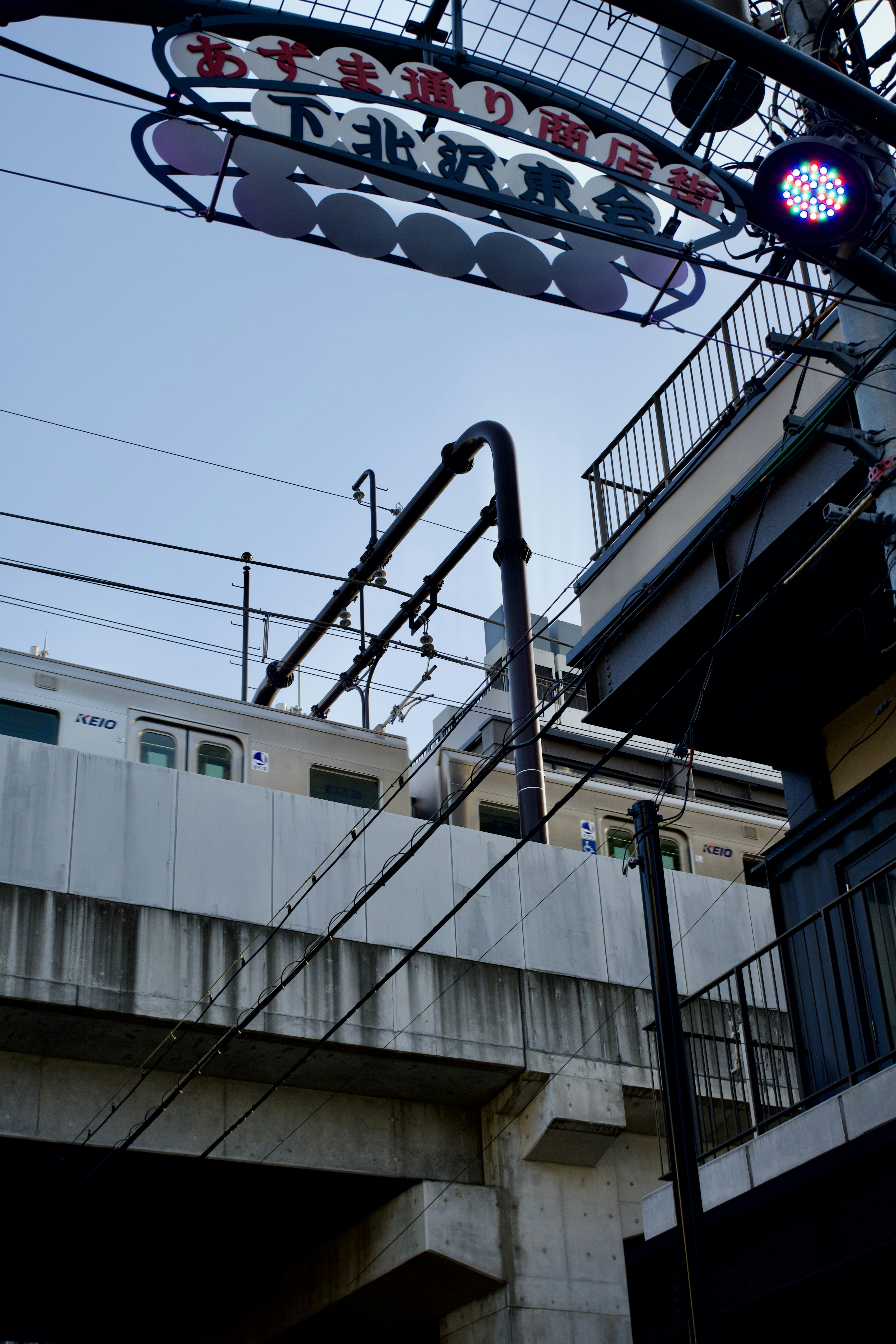 Overhead Rails and Neon Sign: Urban Crossing Above the Station