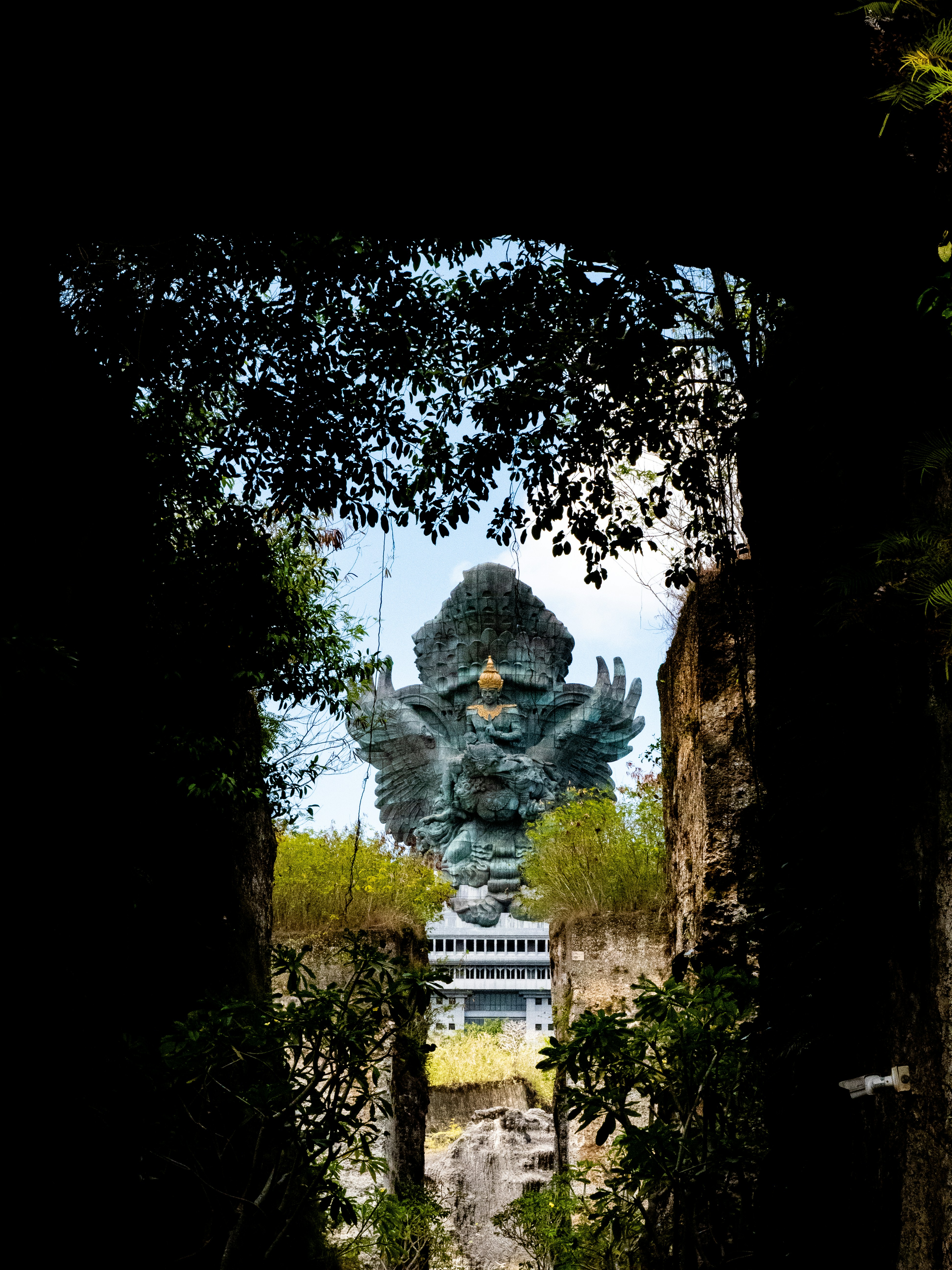 Through the Ancient Gate: A Dragon Statue Emerges in Dappled Light