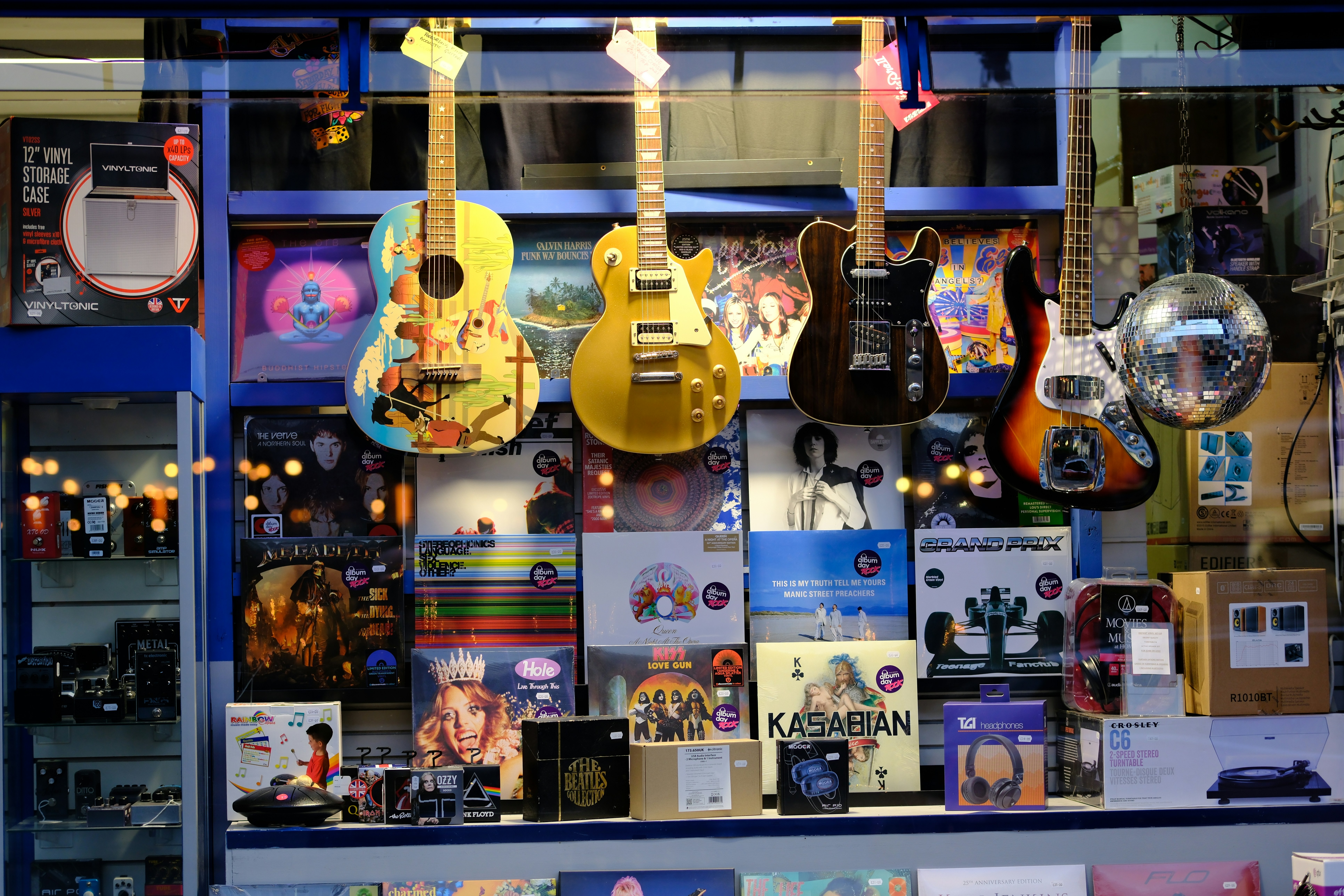 Guitars in a storefront window: a chromatic chorus of colors and reflections