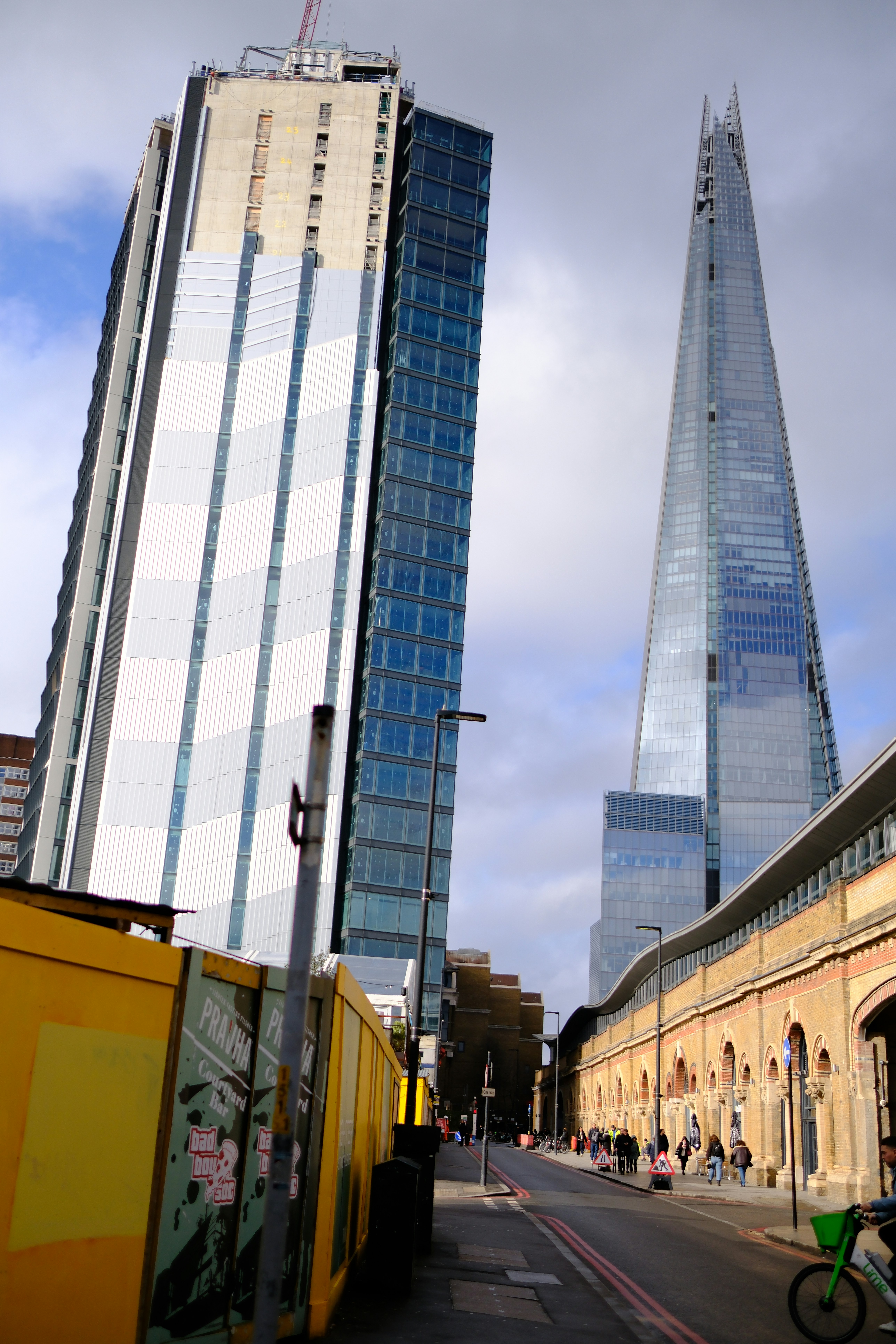 Towering Glass and City Painters: A Street-Scale Perspective of The Shard-like Spire and Active Railway Brick Arc