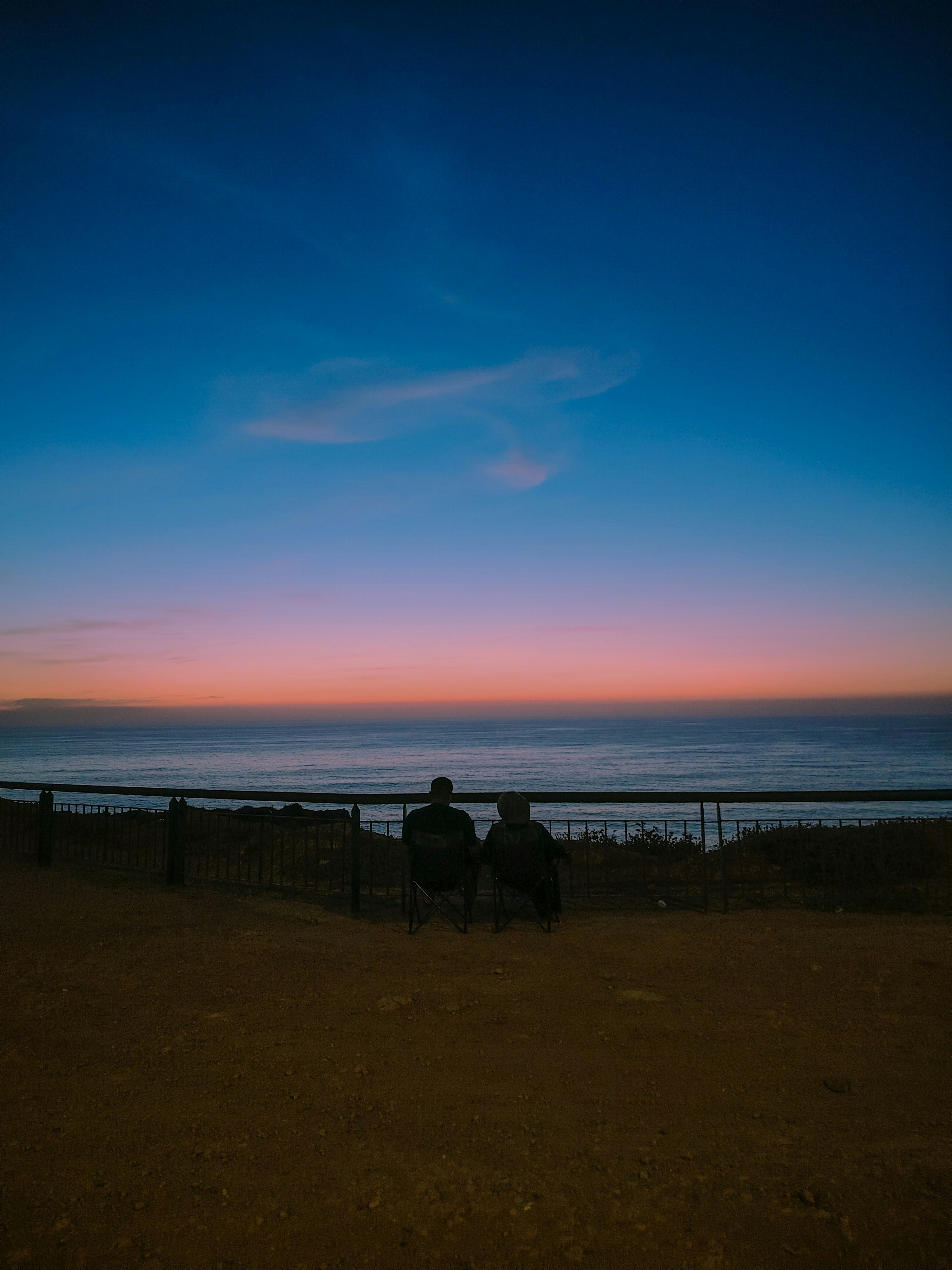 Evening by the Rail: Two Silhouettes at the Quiet Sea