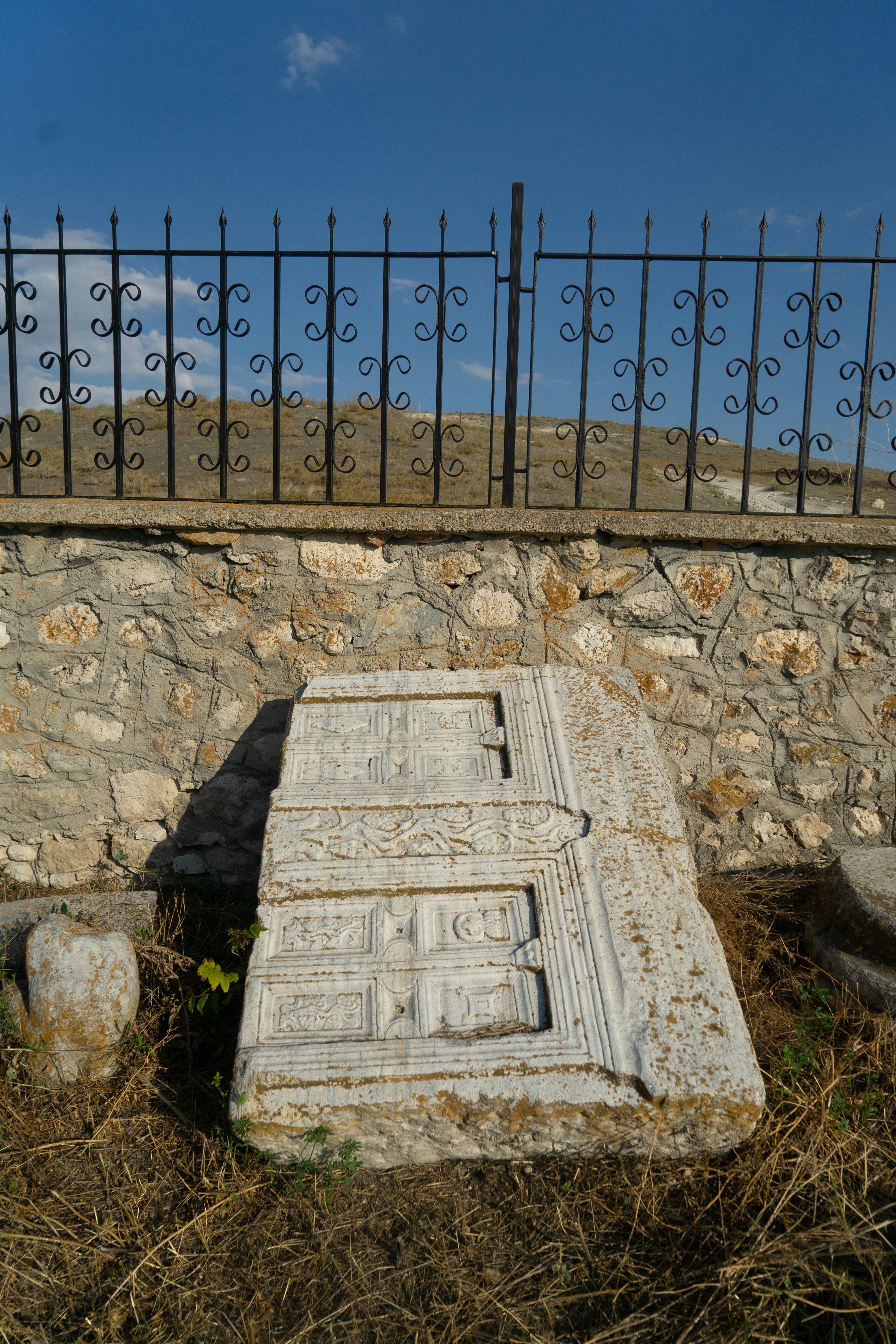 Stone Tablet Beneath a Wrought-Iron Fence: Echoes of a Quiet Hill