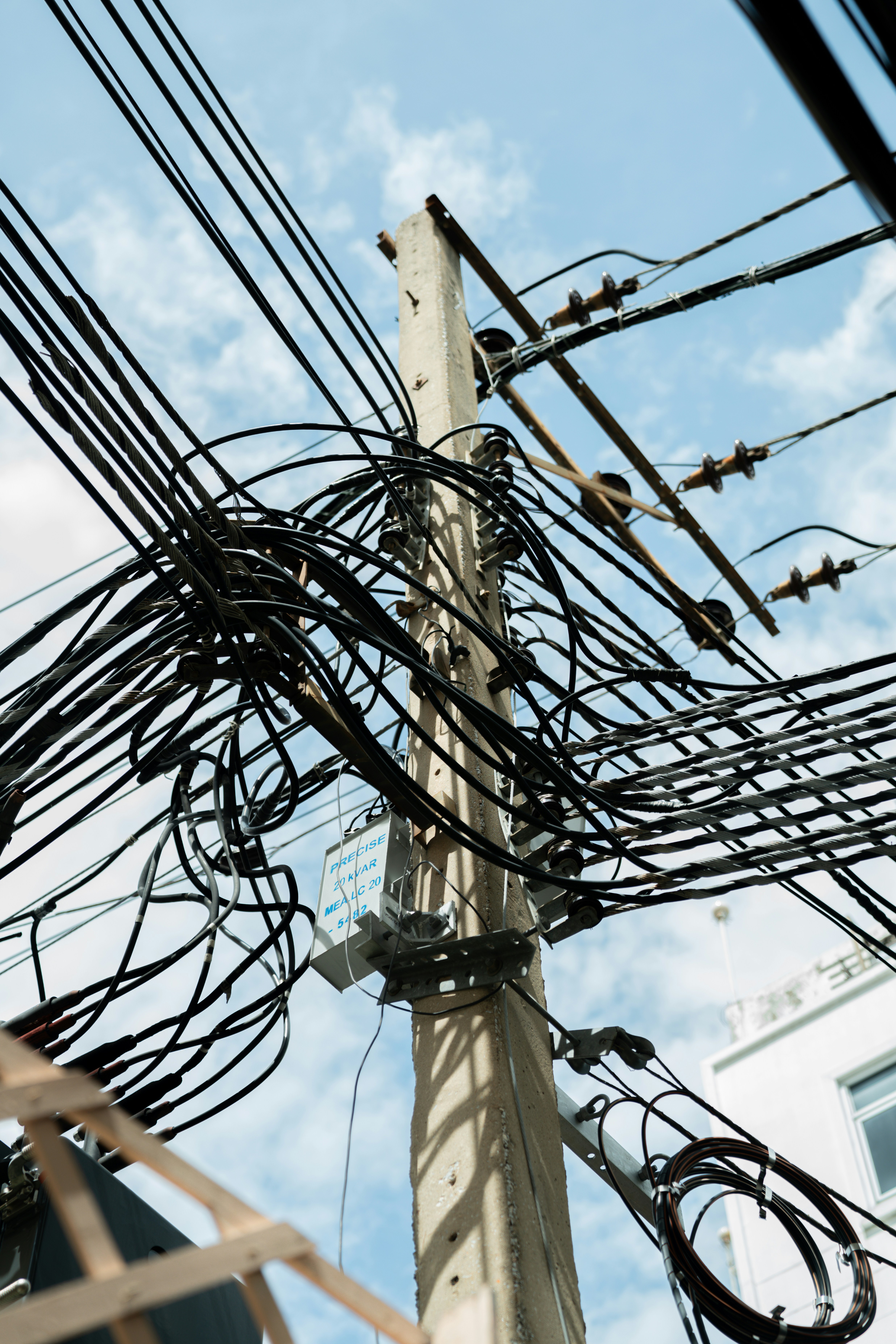 Tangled Signals: A Portrait of Cables and a Weathered Pole Against a Bright Sky