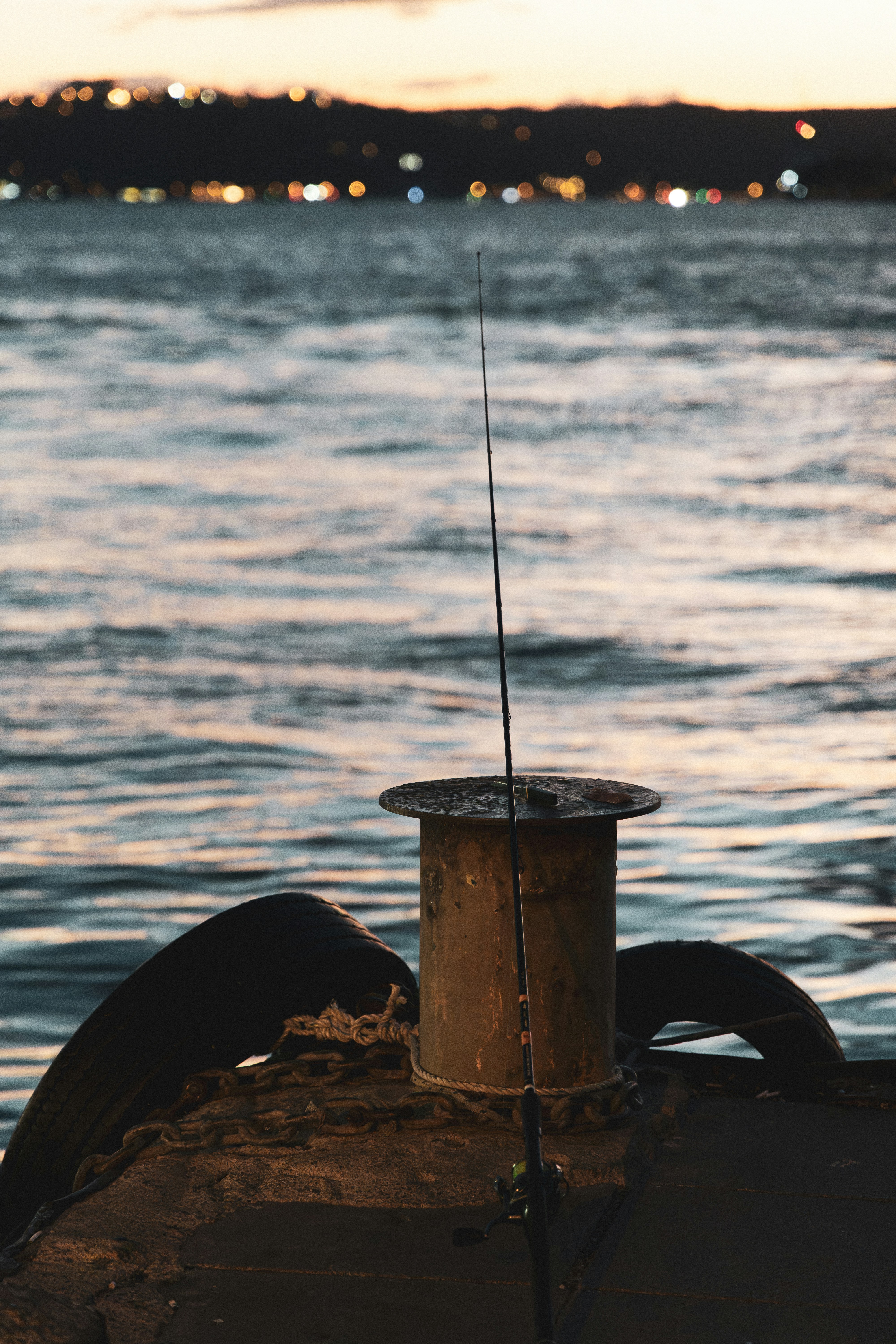 Rusted reel on the quay: a lone fishing line reaches toward a moonlit horizon