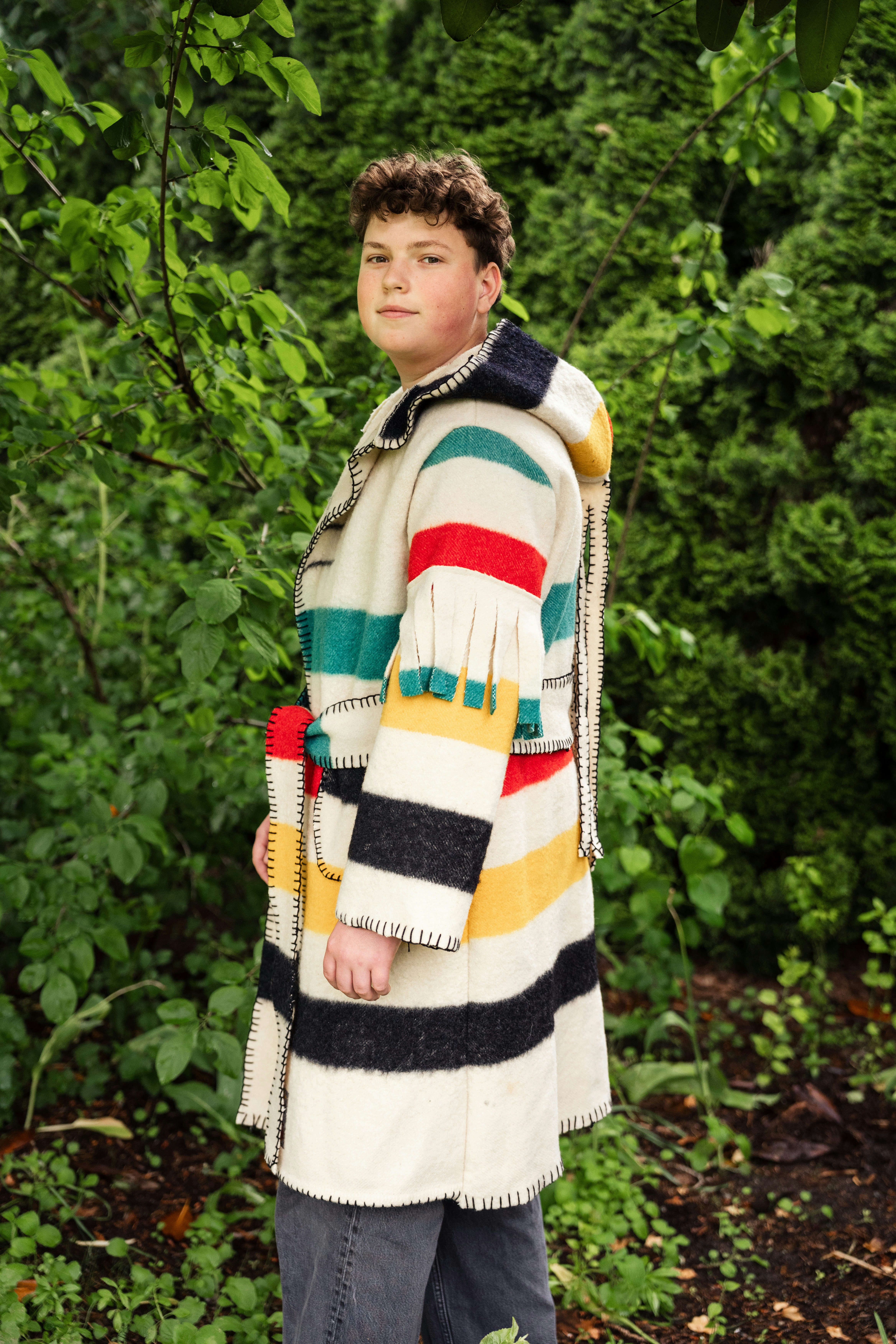 Portrait in Color Blocks: A Youthful Figure in a Striped Coat Flush with Greenery