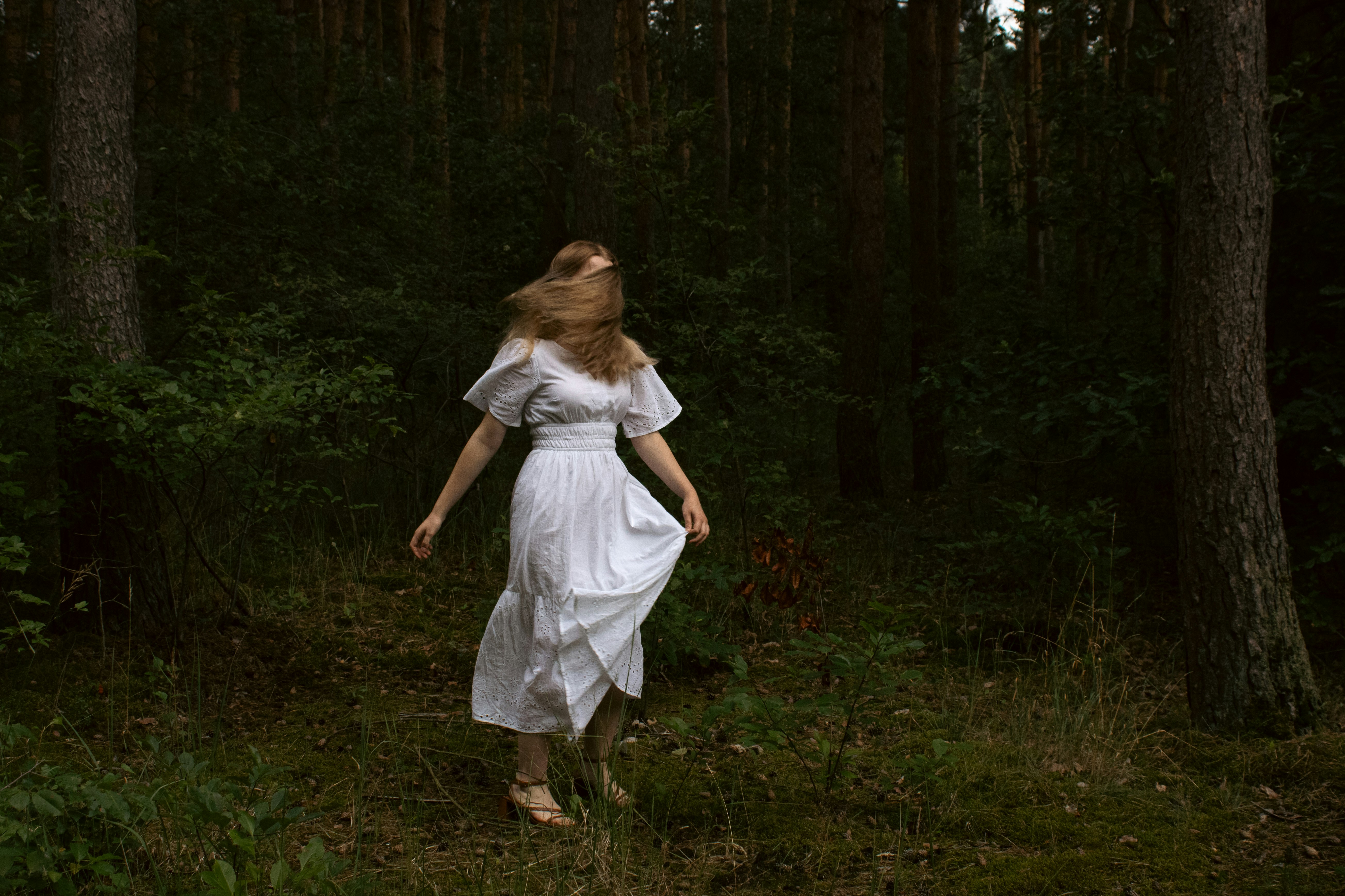 Whispers in White: A Woman Draped in Light Walks the Edge of the Forest
