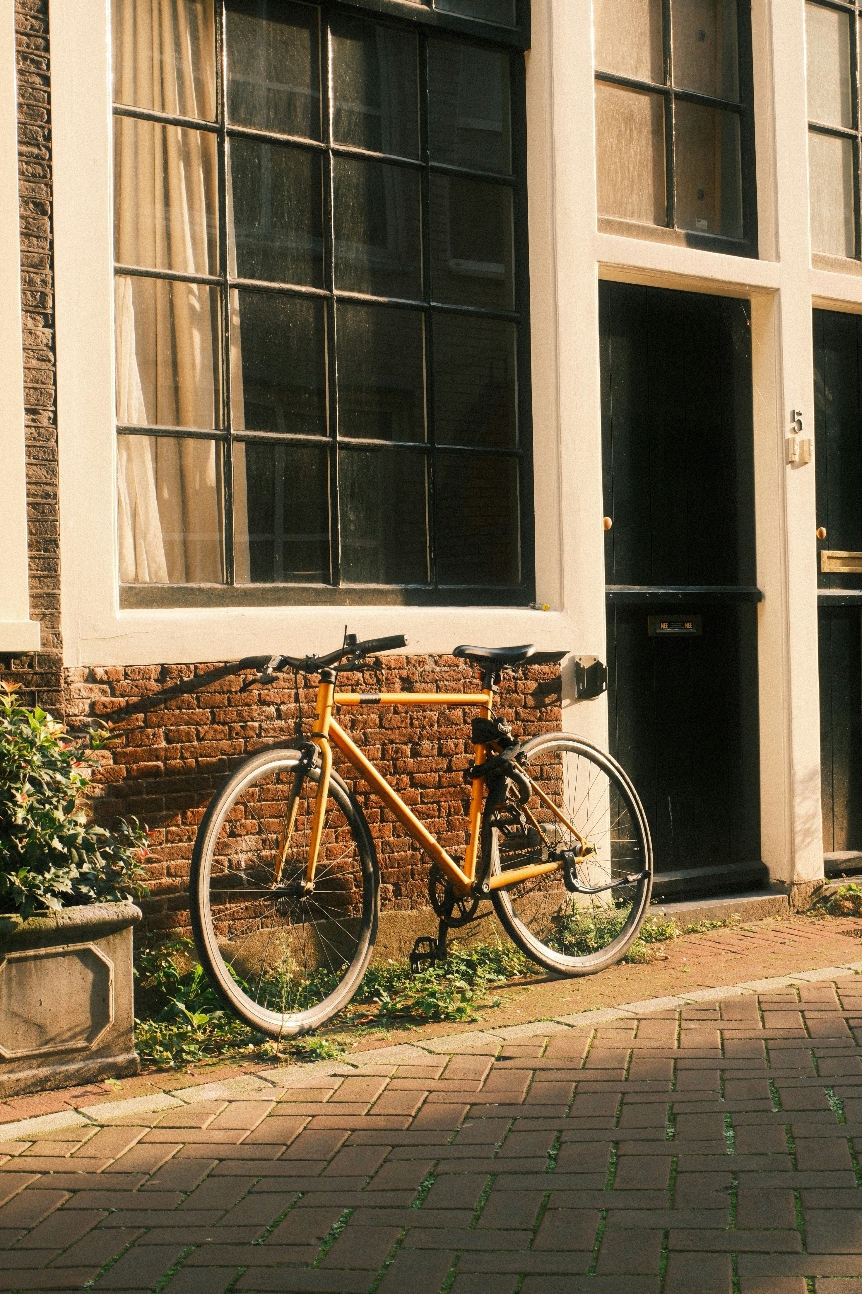 Yellow Riderless: A Quiet Bicycle Resting Before a Brick-Side Street