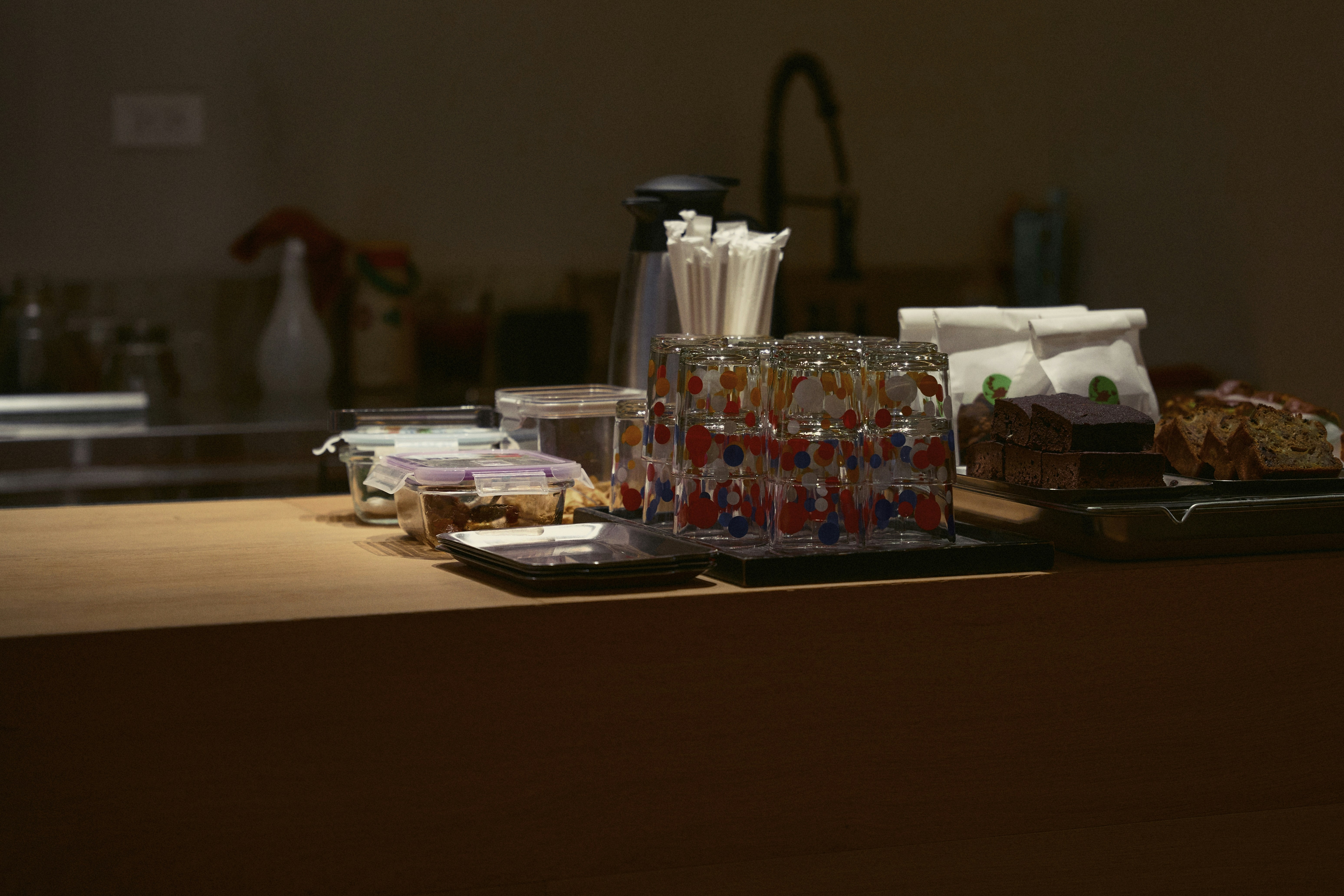Dimly Lit Buffet at Dusk: Sweet Treats and Glassware Under Soft Spotlight