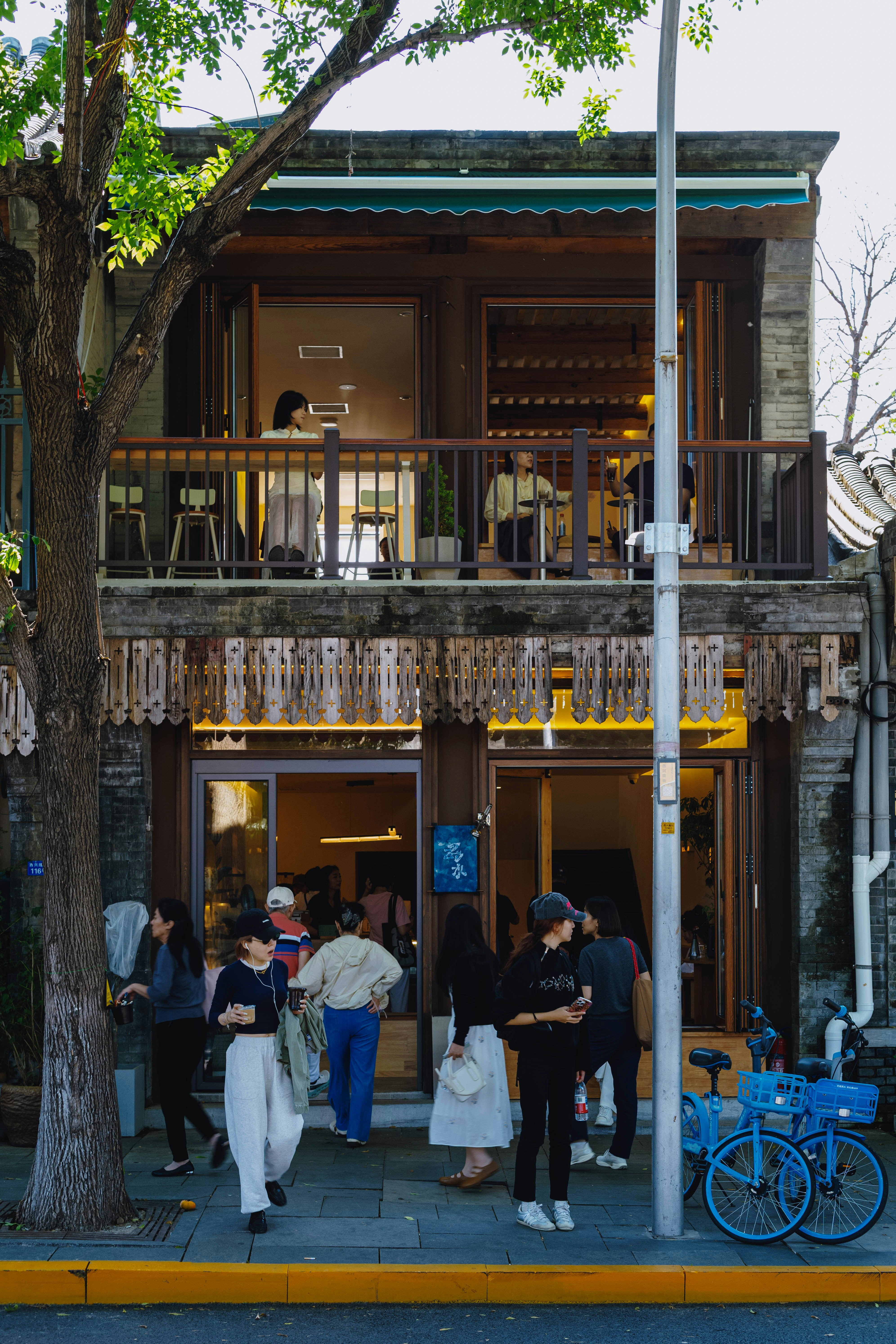 Ground-floor Café Pulse: People Gather as Doorway Opens to Warm Activity
