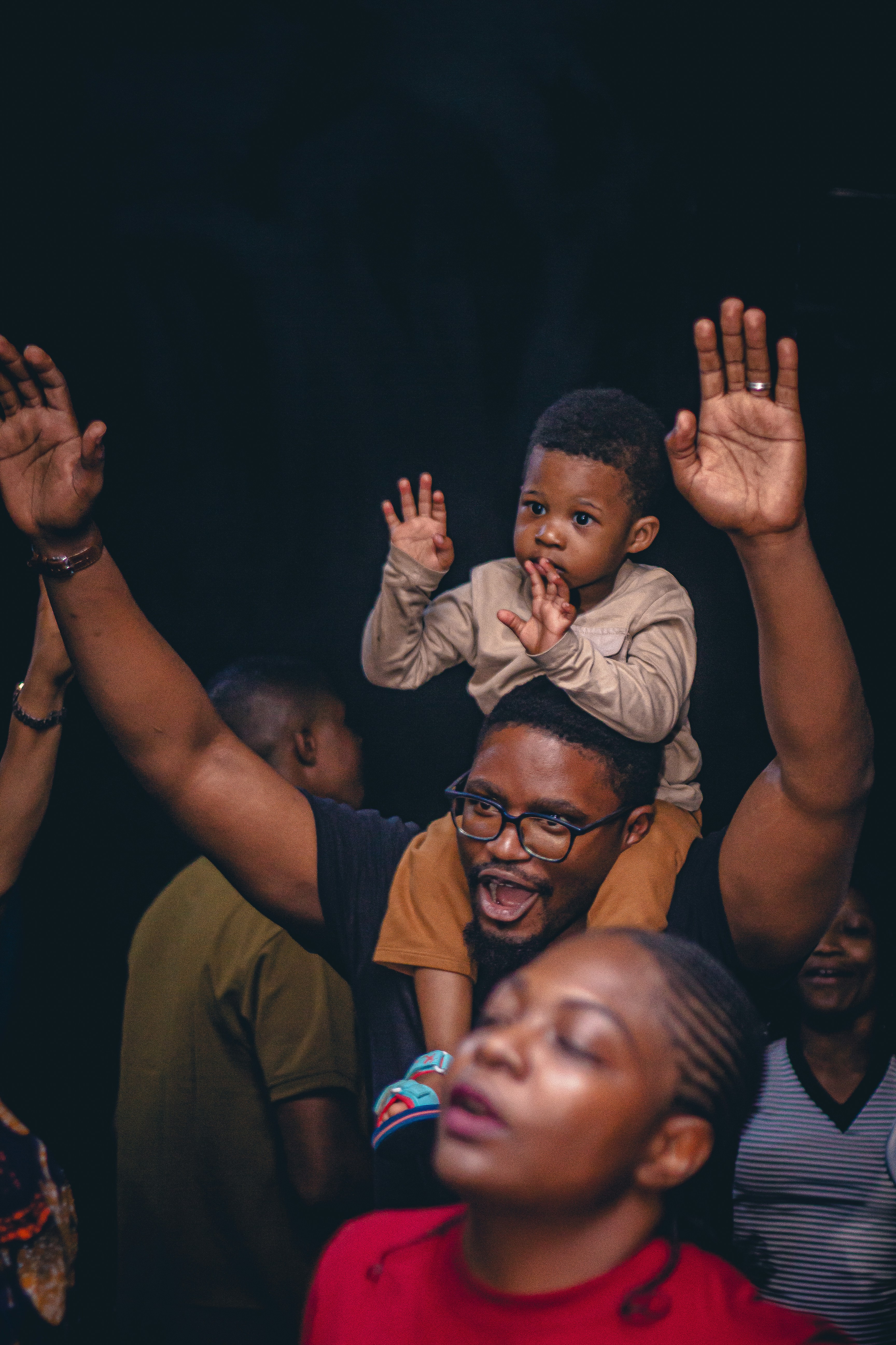 Raised Hands, Shared Moment: Father and Child Amid a Joyful Crowd