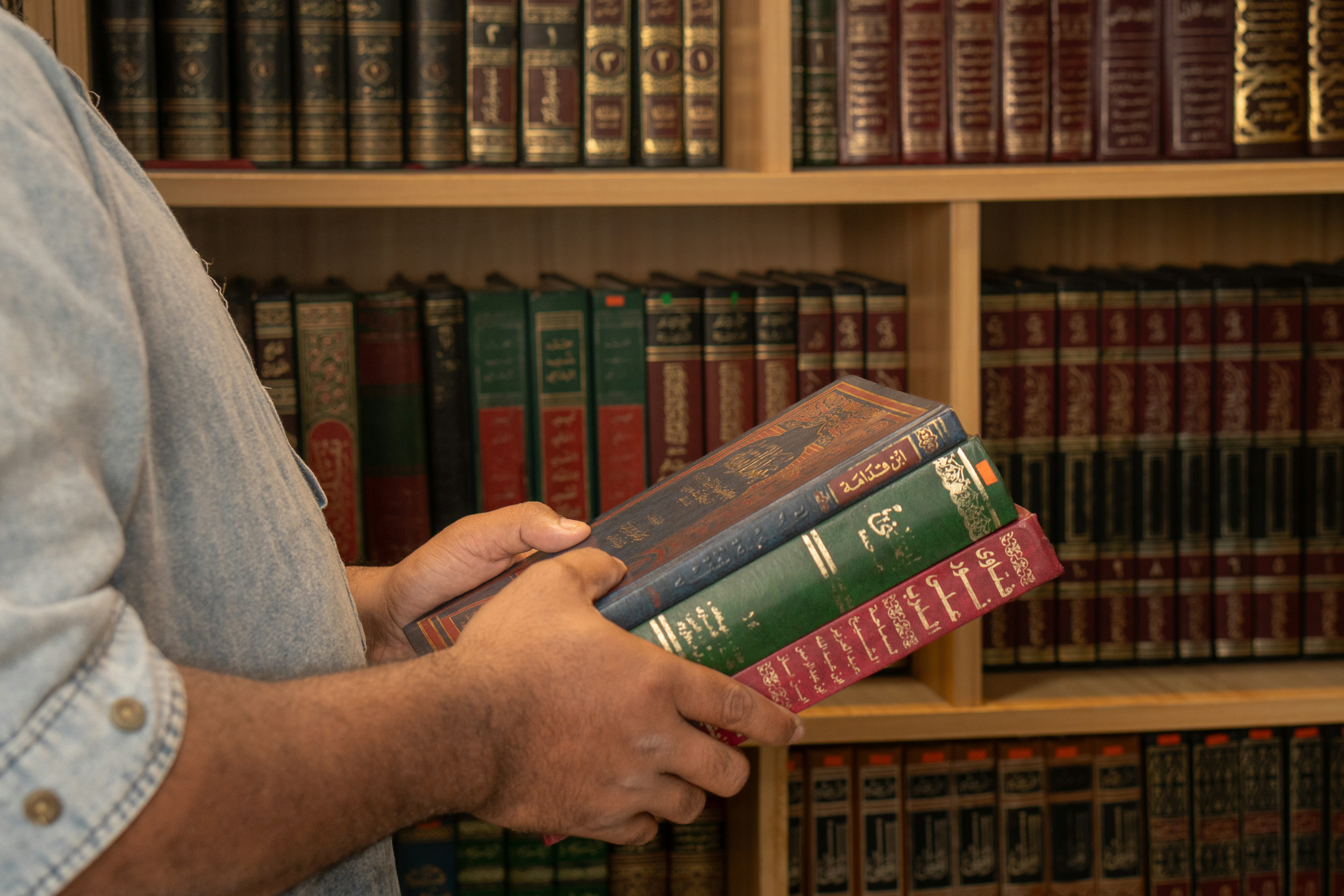 Shelved Knowledge: A Quiet Hand Grips a Stack of Timeless Texts
