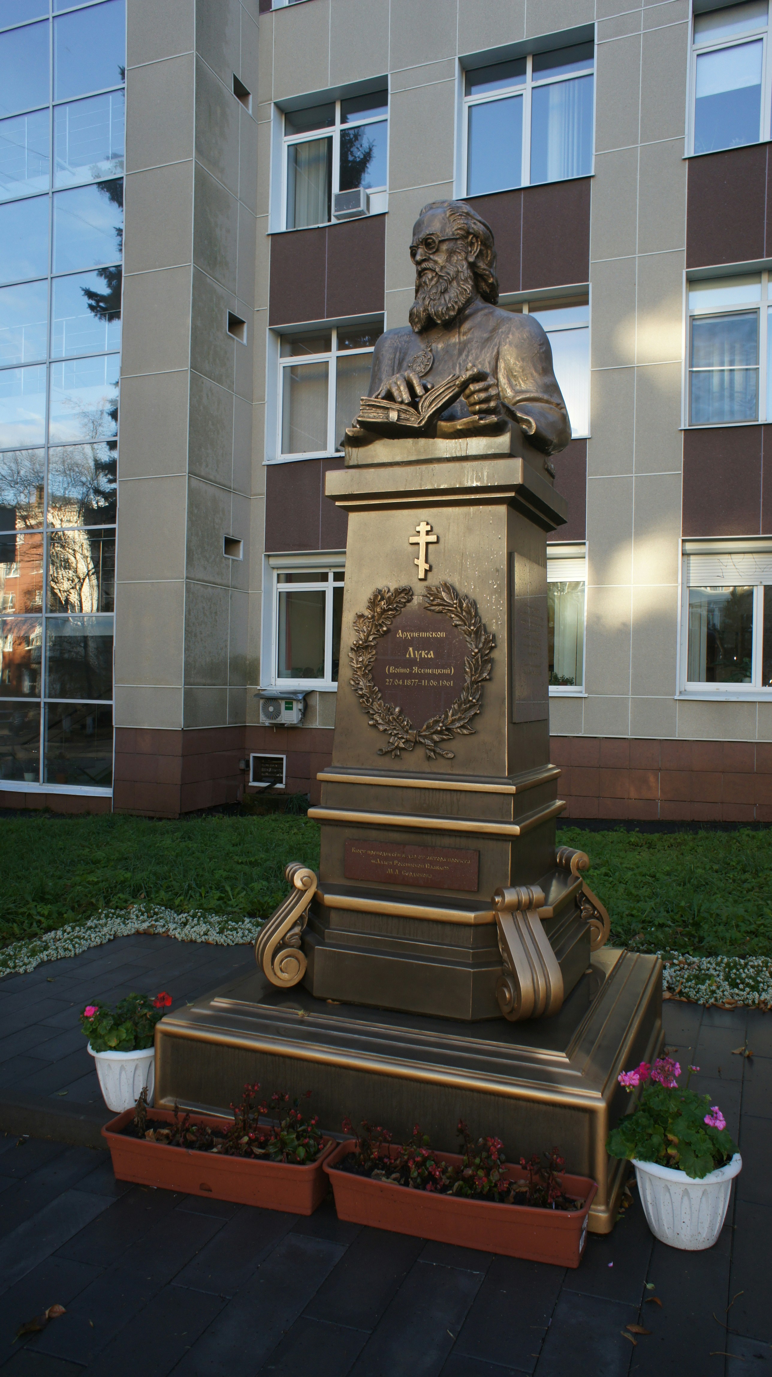 Bronze scholar: a seated bust statue reading aloud in front of a modern building