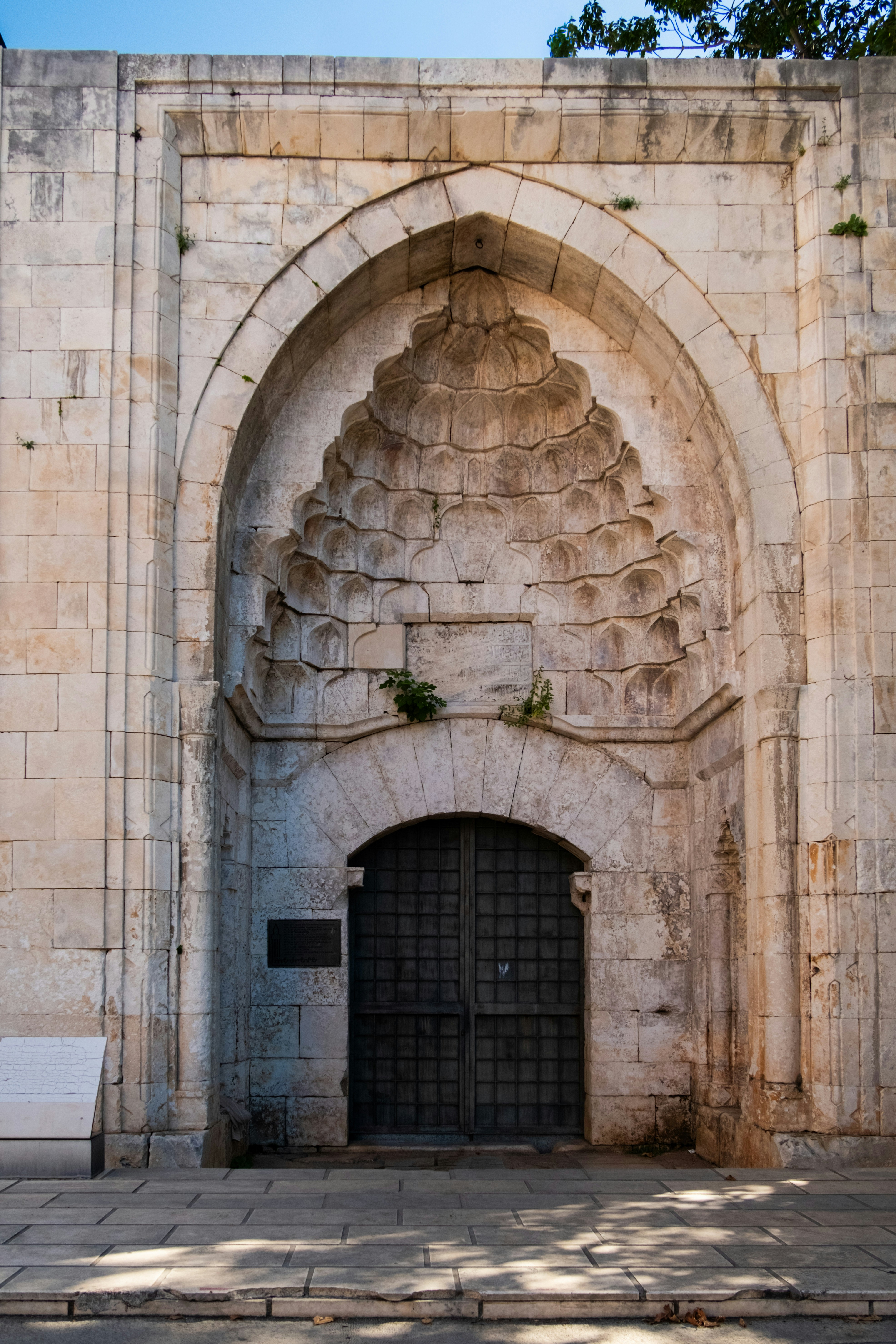 Stone Archway of Time: Carved Conch Ornament Above a Heavy Door