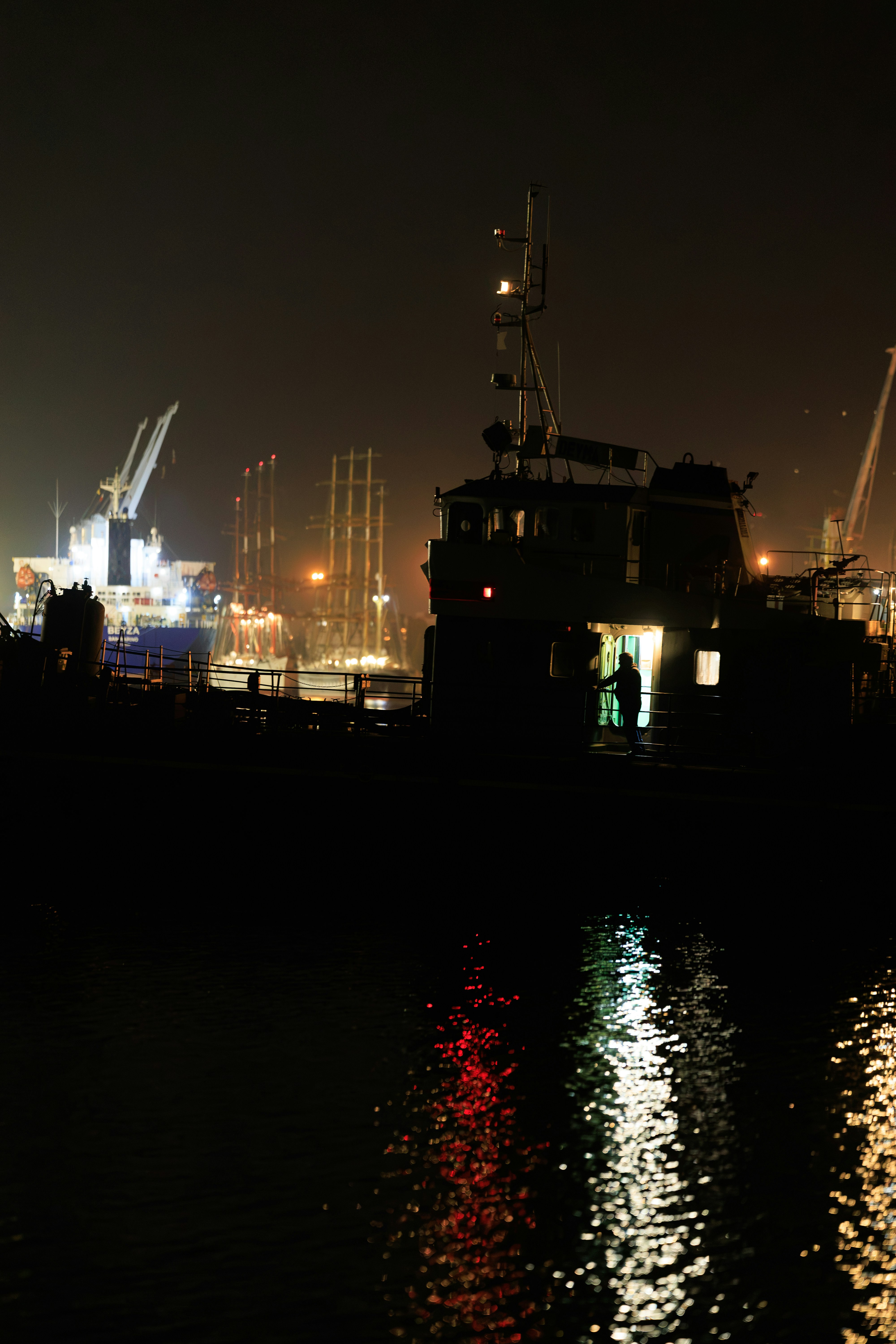 Night Harbor: A Crane-lit Vessel and Quiet Reflections on Dark Water