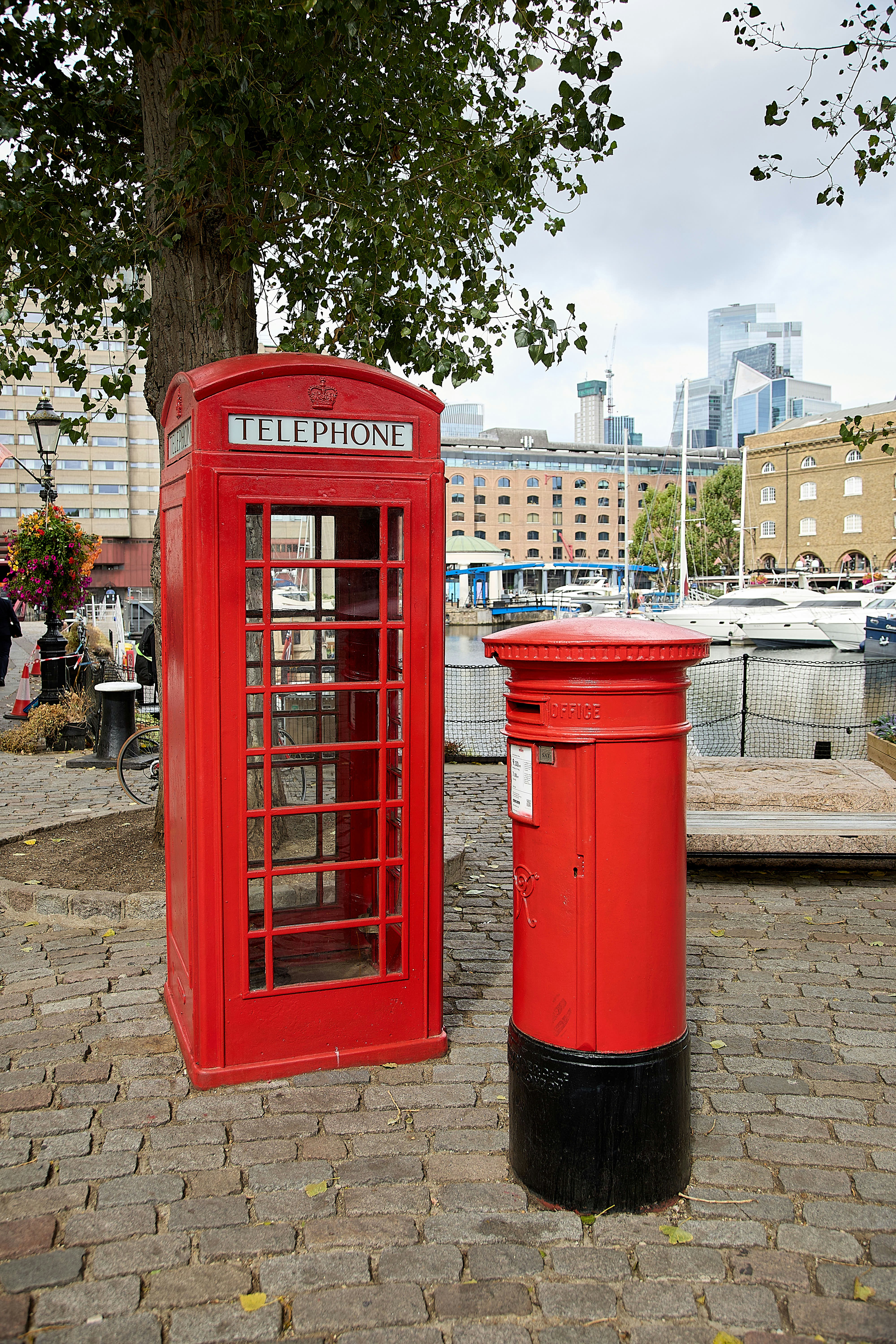 Red London in the Harbor: A Phone Booth and Post Box Framed by Waterfront Bricks