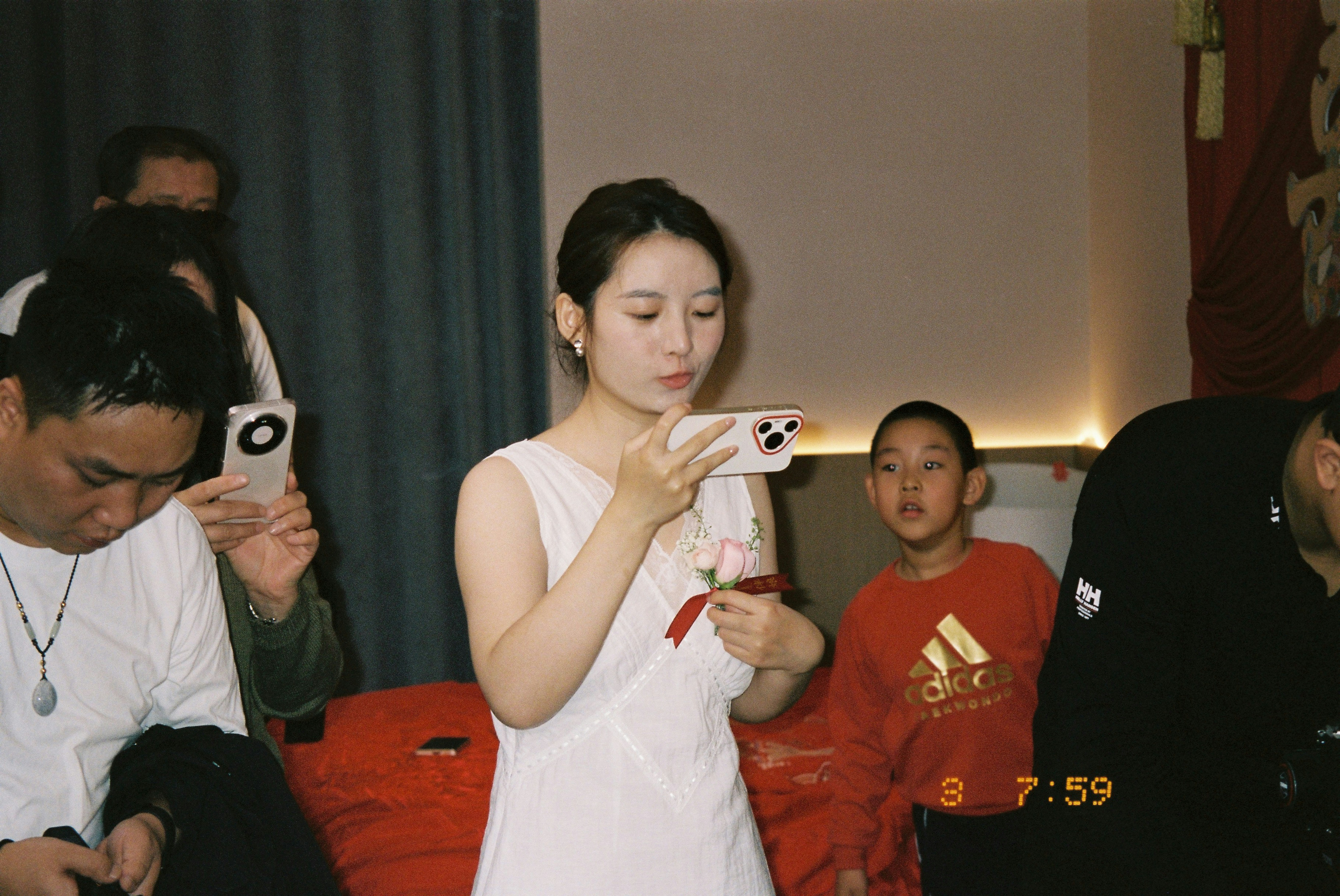 Centered Moment: A young woman in white checks her phone amid a casual, busy room