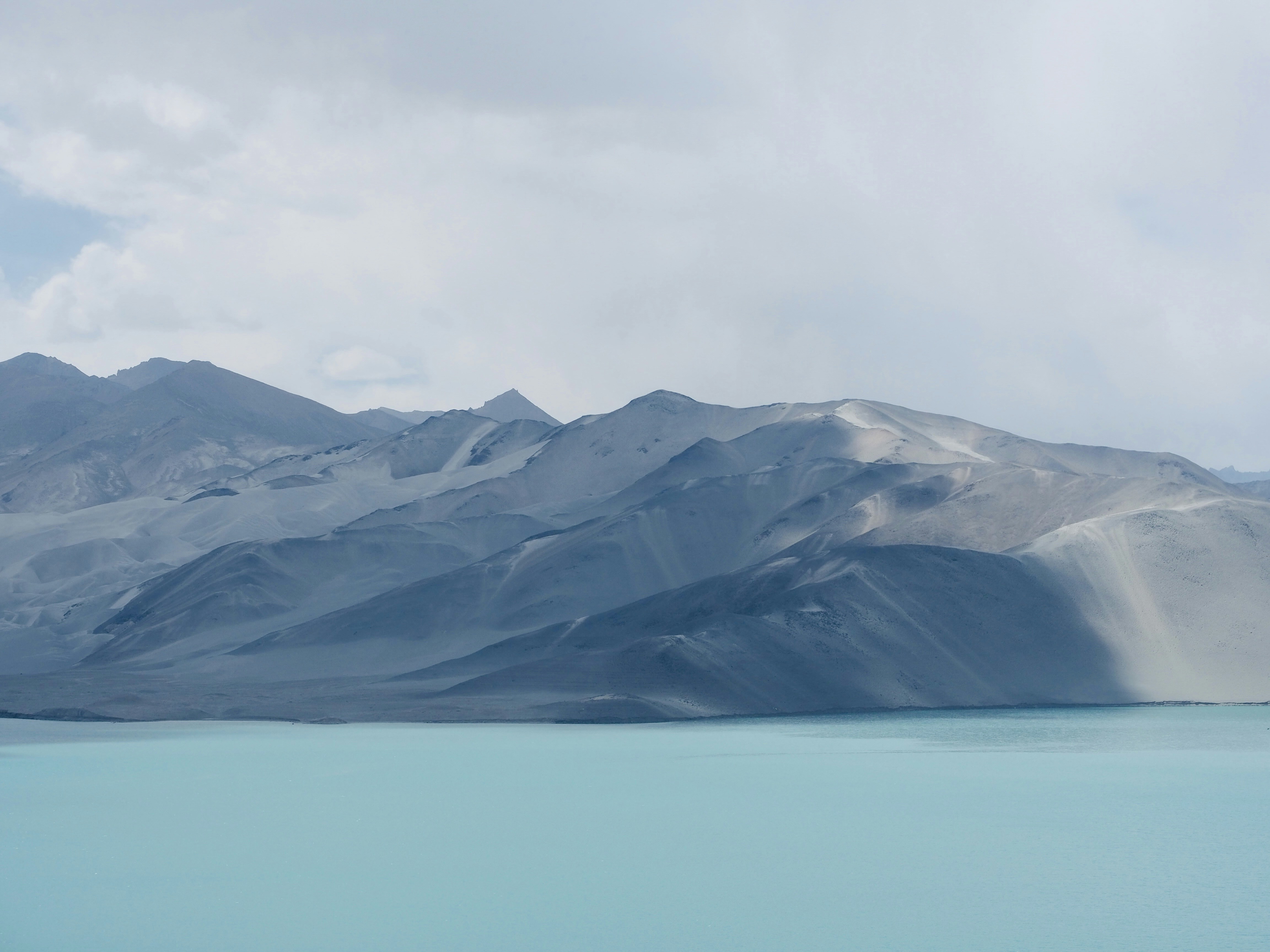 Turquoise Shoreline Beneath Blue-Gray Peaks