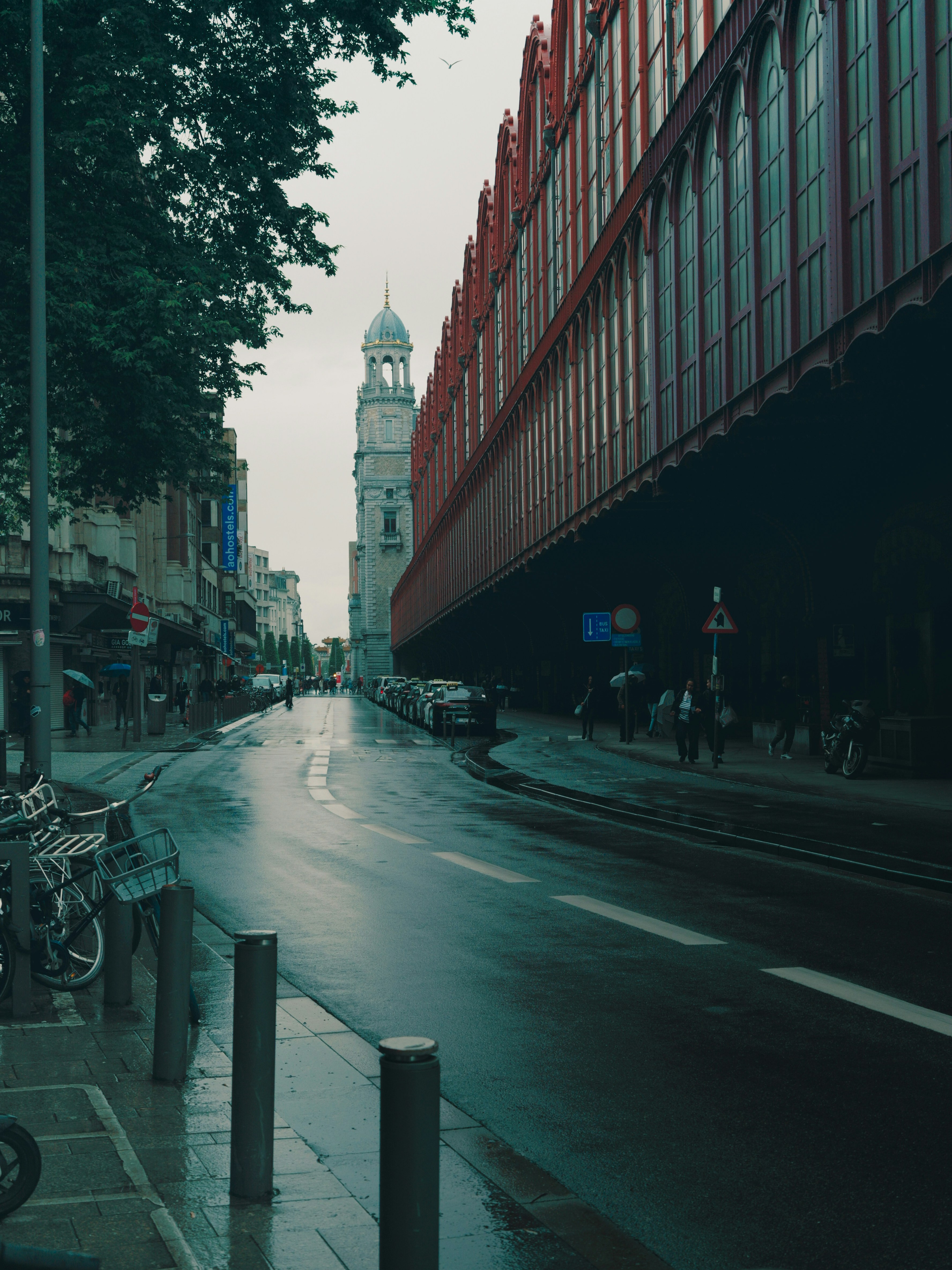 Toward the Clock Tower: A Rain-Slick City Street Under a Red Eave