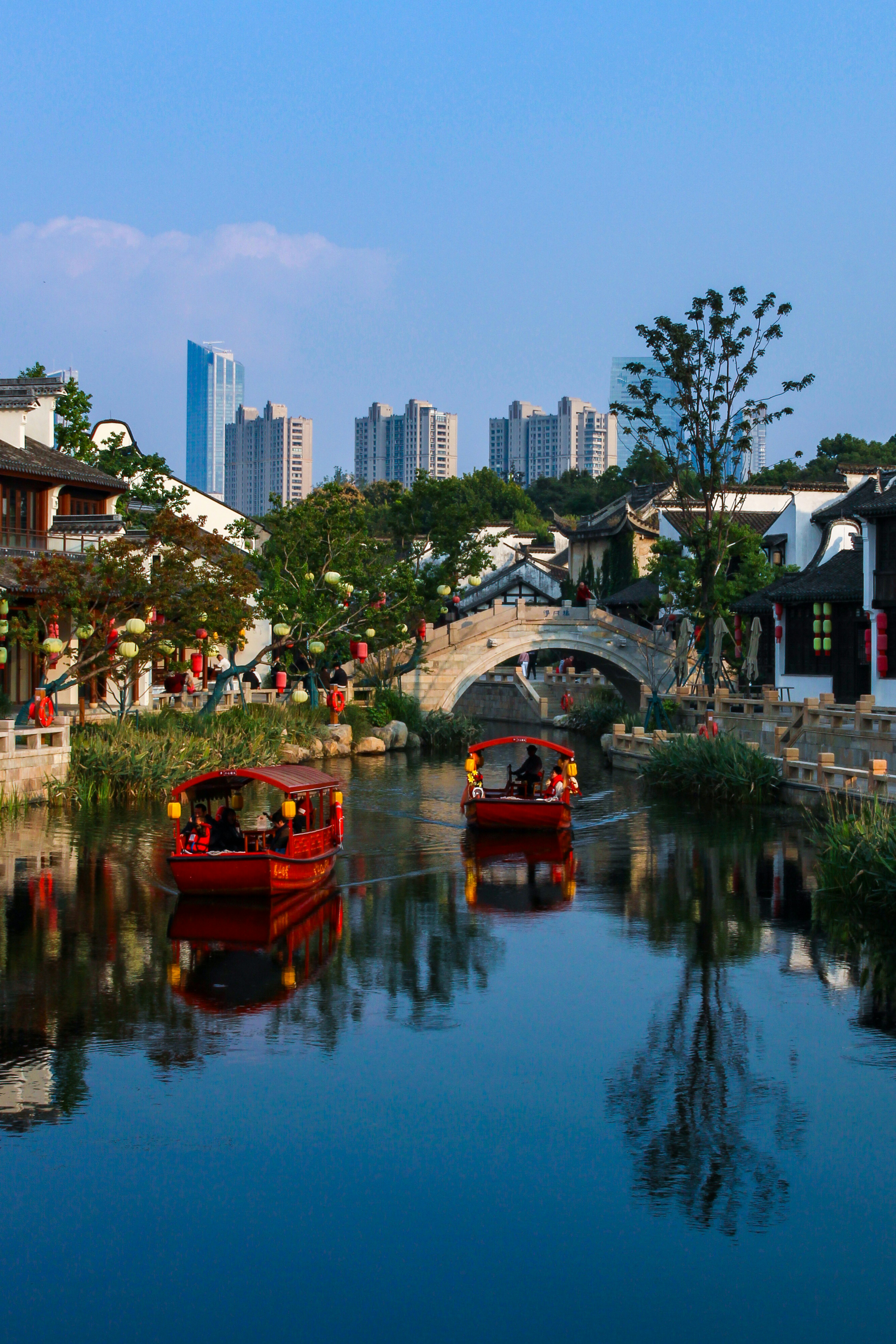 Red Boat Reflections beneath a Stone Bridge in a Pampered Waterway Town