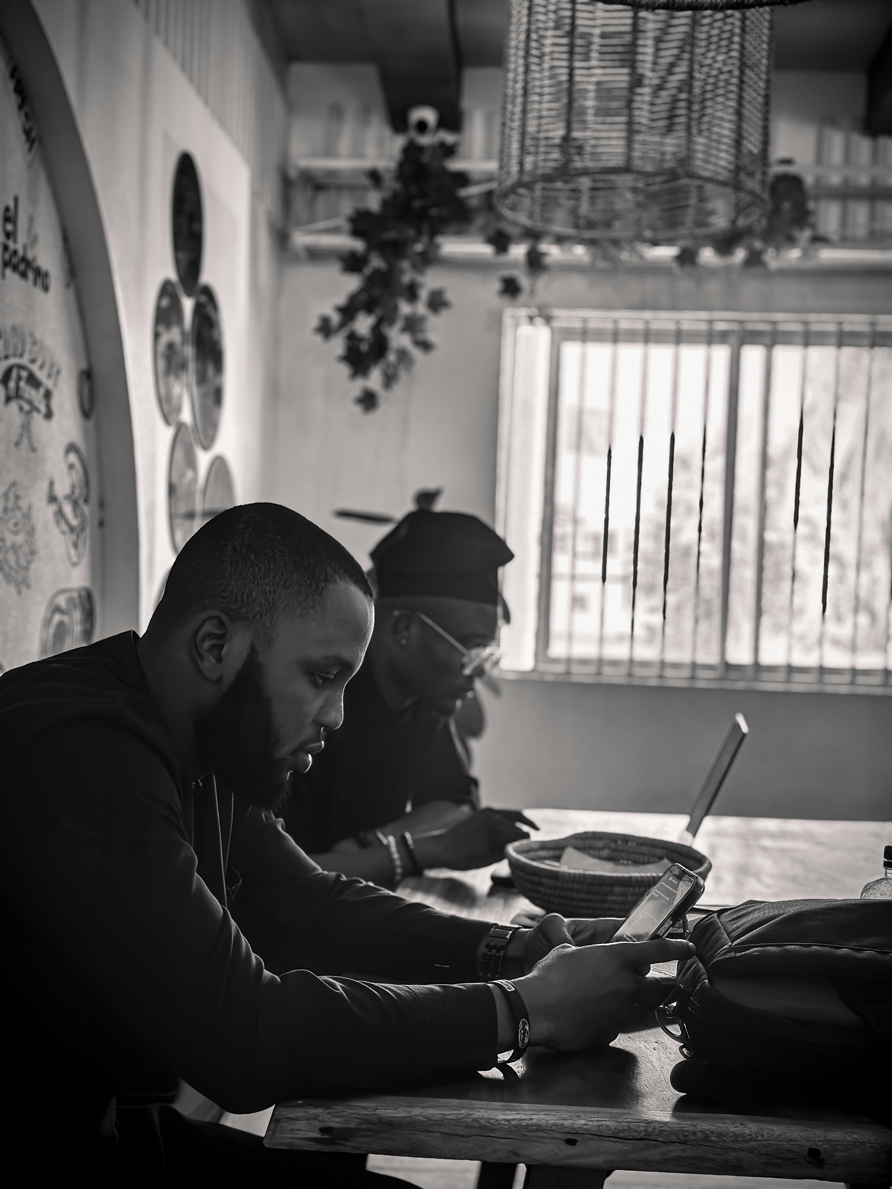 Focused Moment: Two Friends at a Wooden Table in Soft Natural Light
