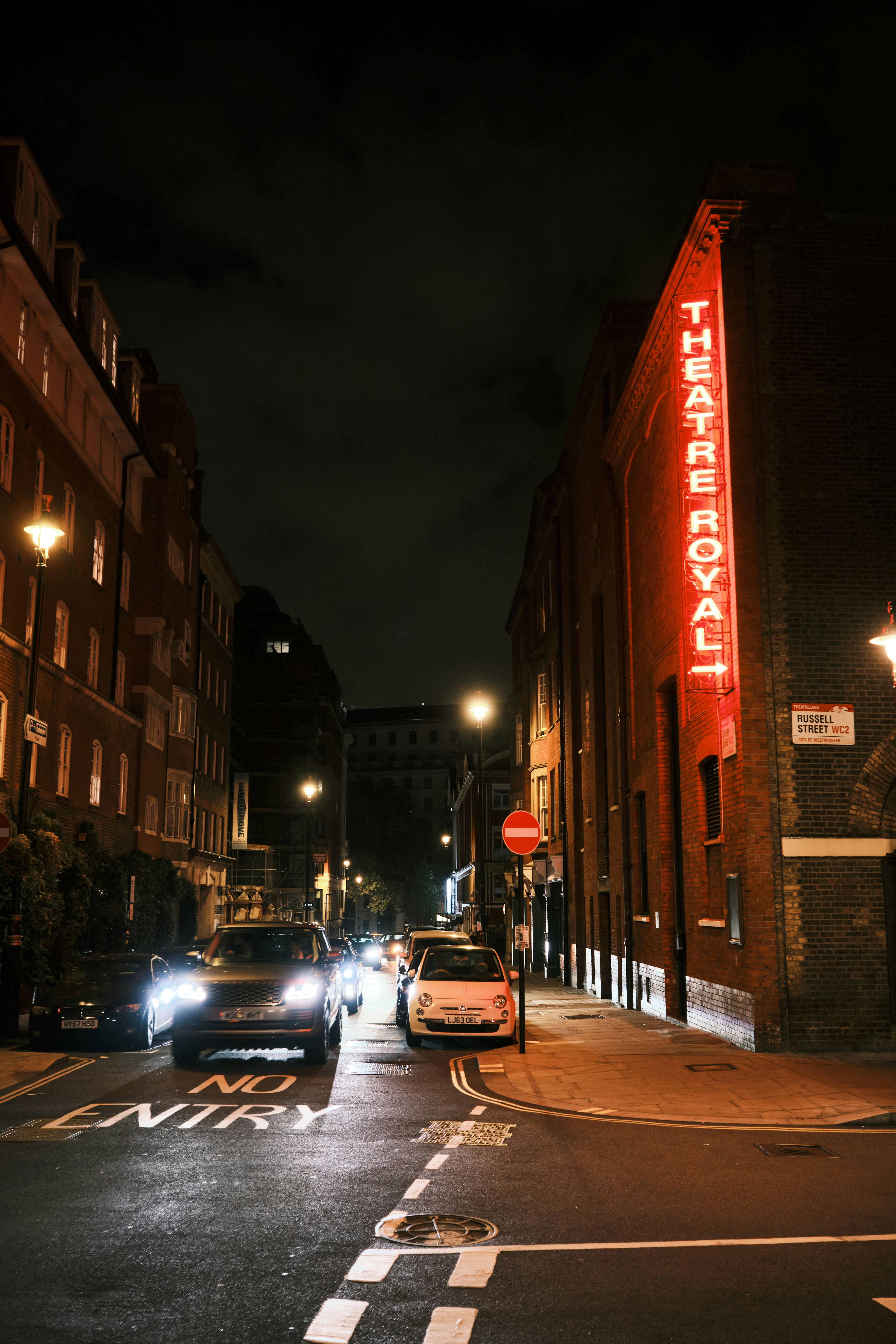 Neon Theater Wake Across a Quiet Night Street