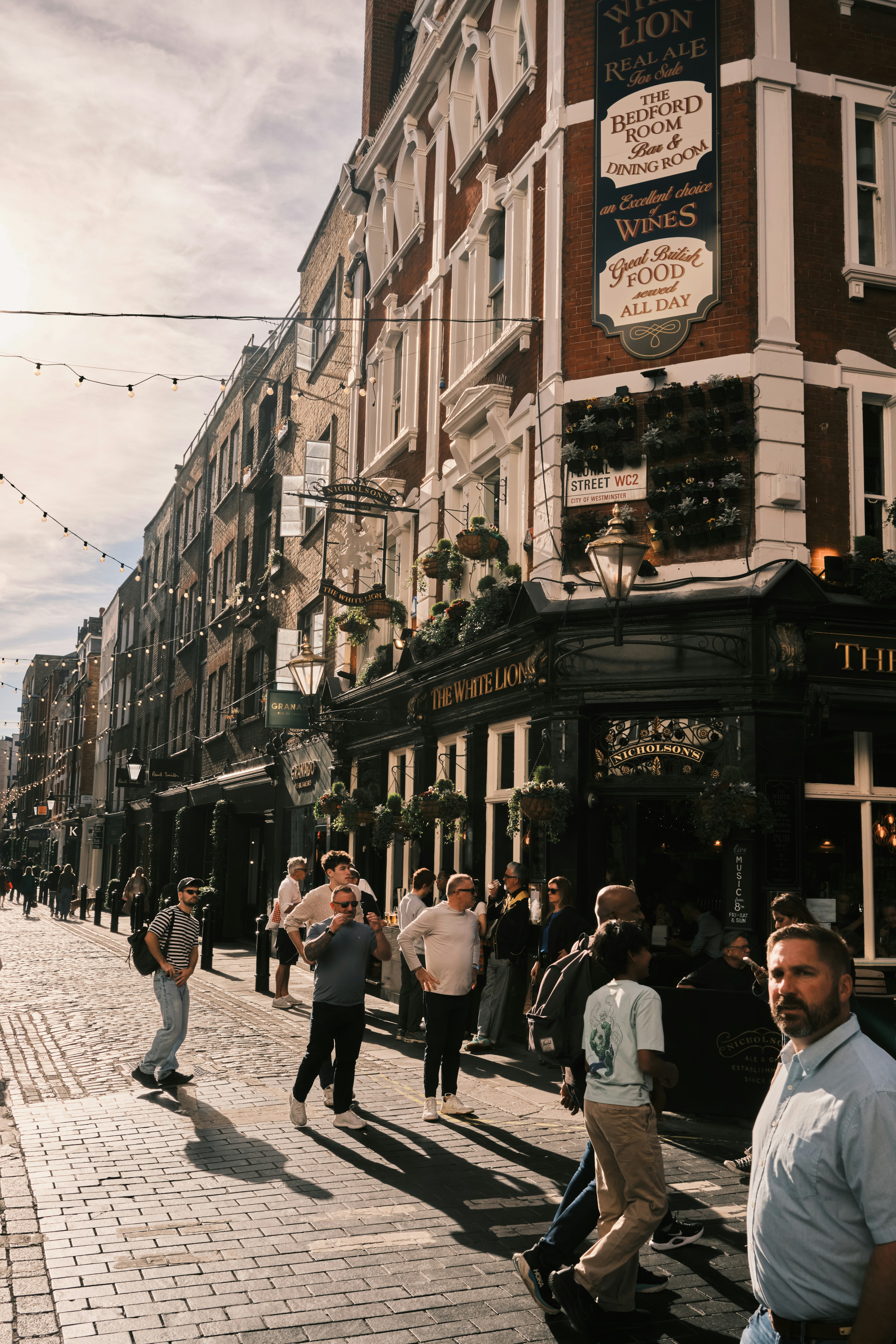 People walking on a cobblestone street past The White Lion pub in London