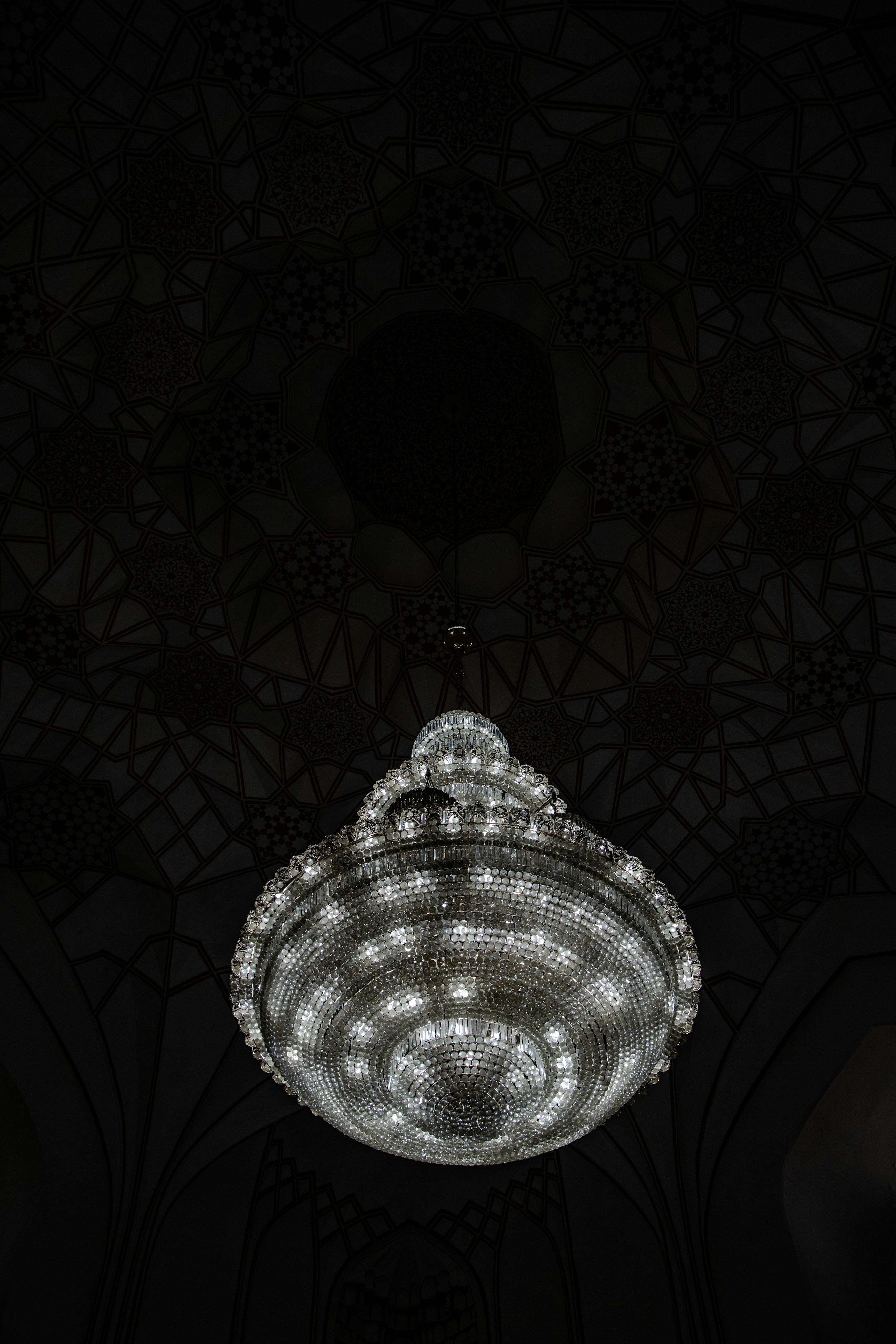Crystal Constellation: A Haloed chandelier suspended under ornamental arches