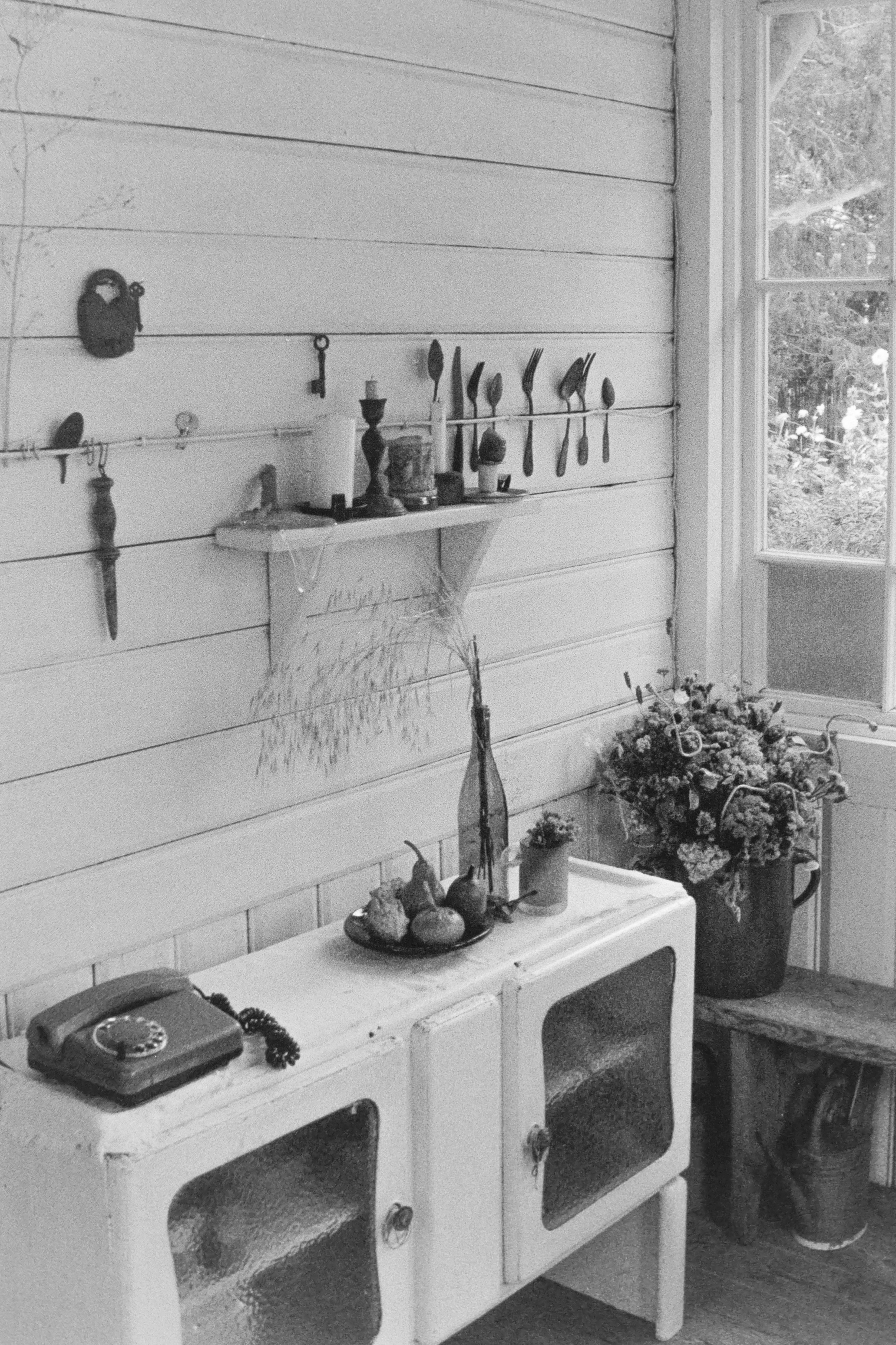Vintage still life in a sunlit corner with ceramic cabinets and herb shelf