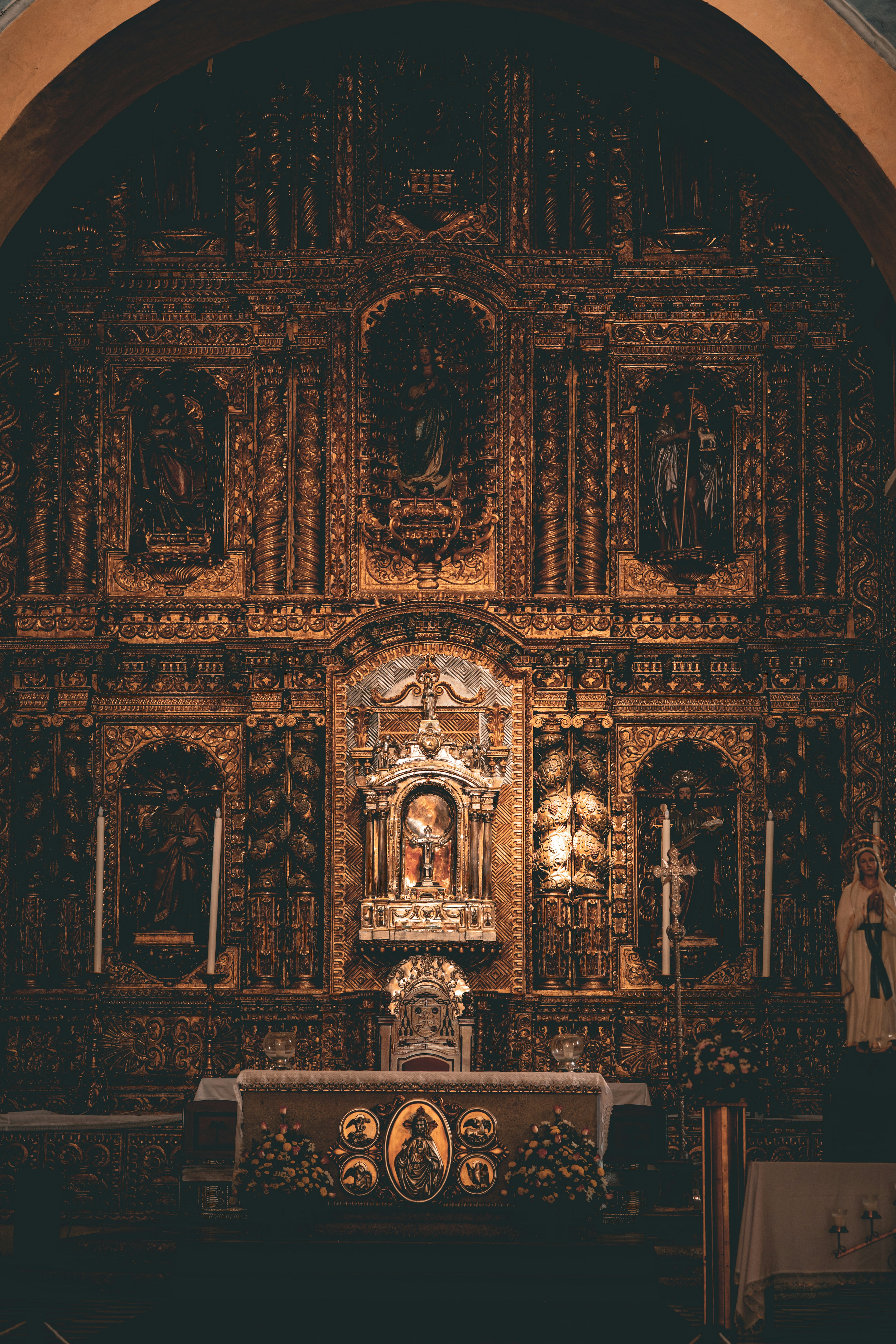 Gilded Altar centerpiece beneath an arch of shadowed devotion