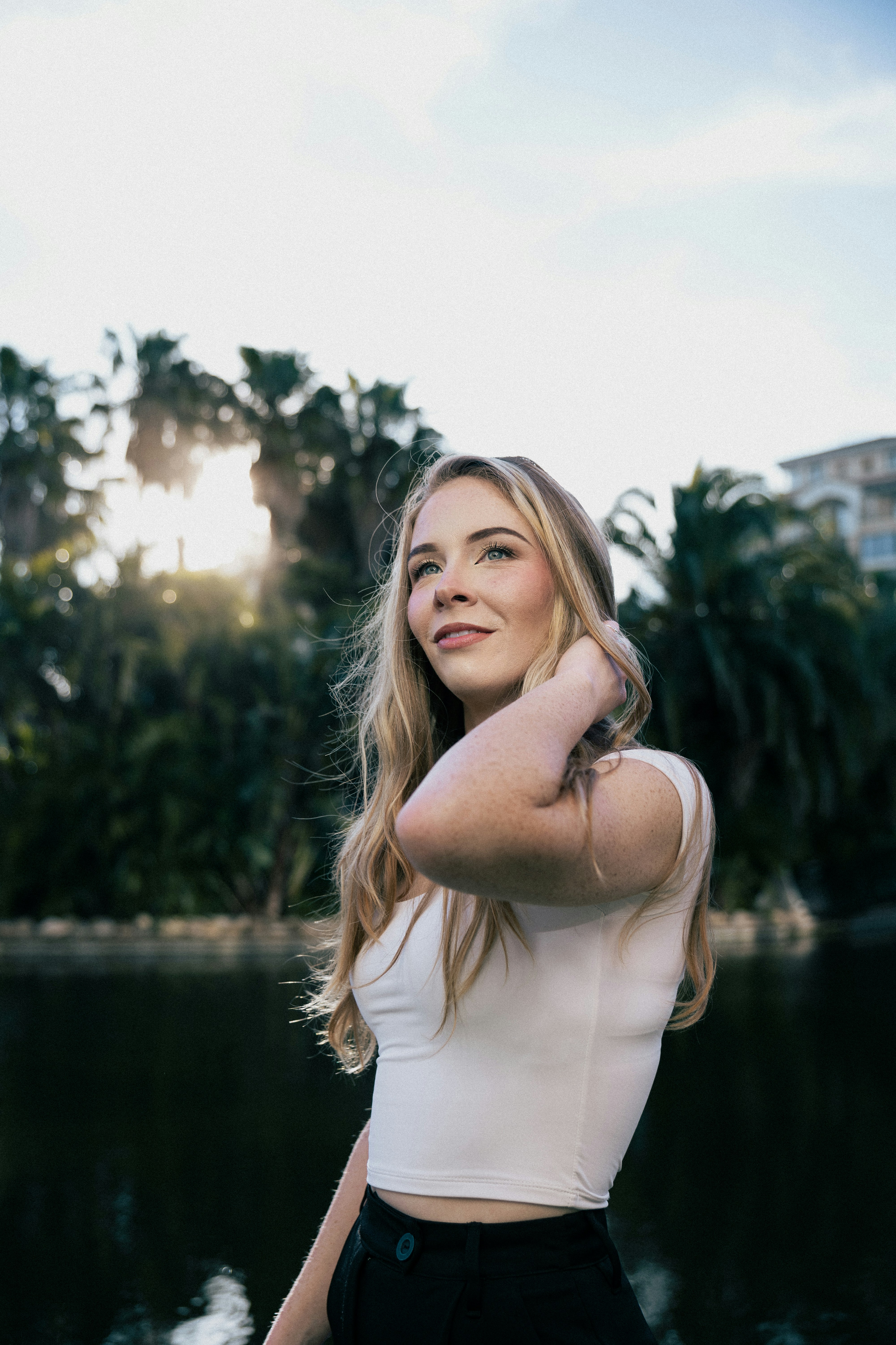 Sunlit Portrait by the Lagoon: A Soft Stare and Wind-Swept Hair