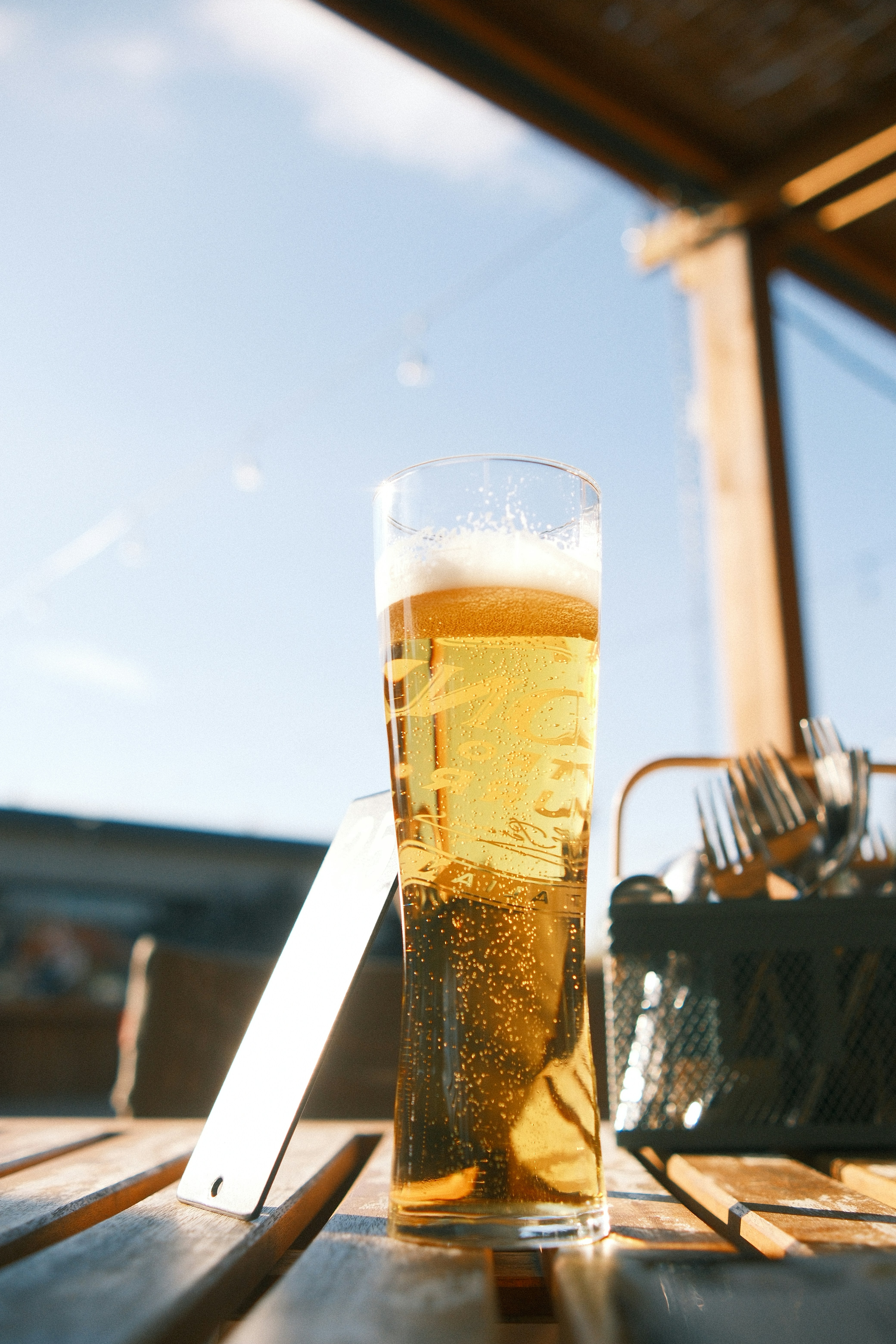 Sunlit Pint: A Tall Glass Takes Center Stage on a Rustic Patio