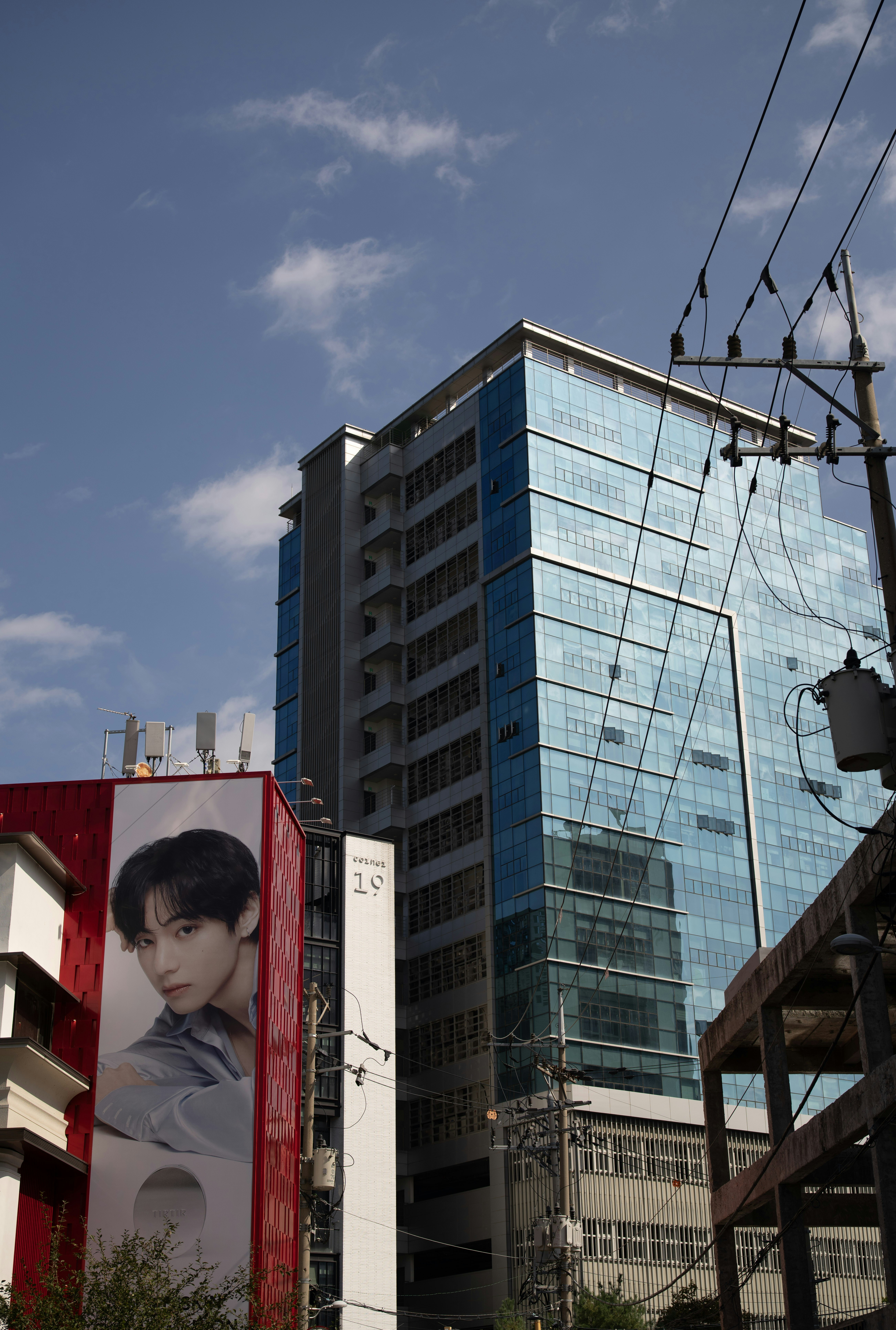 Skylines and Portraits: A Street-Front Ad Tower Framed by Glass and Writ
