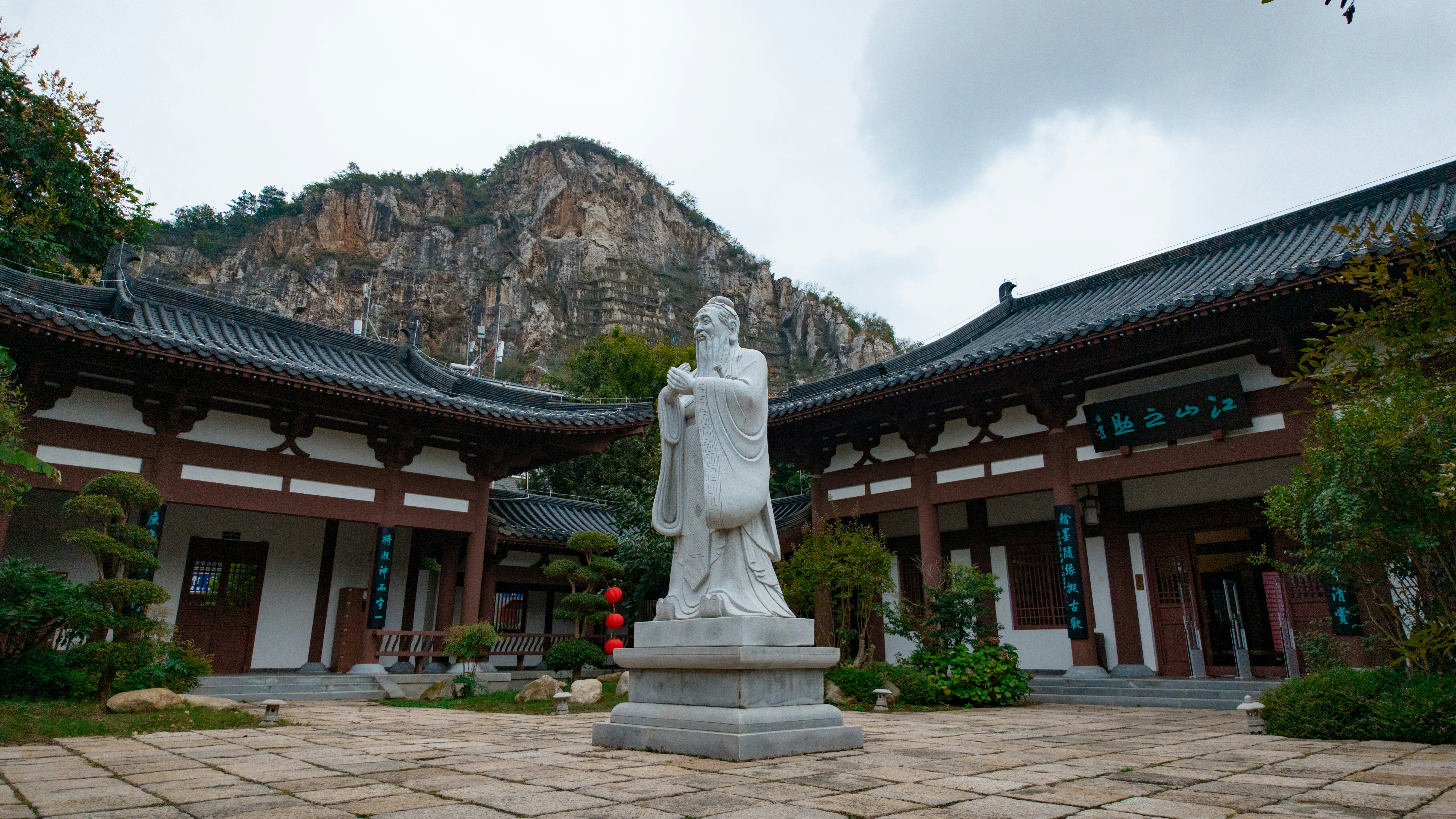 Serene Guardian: A Stone Statue Framed by Traditional Courtyard