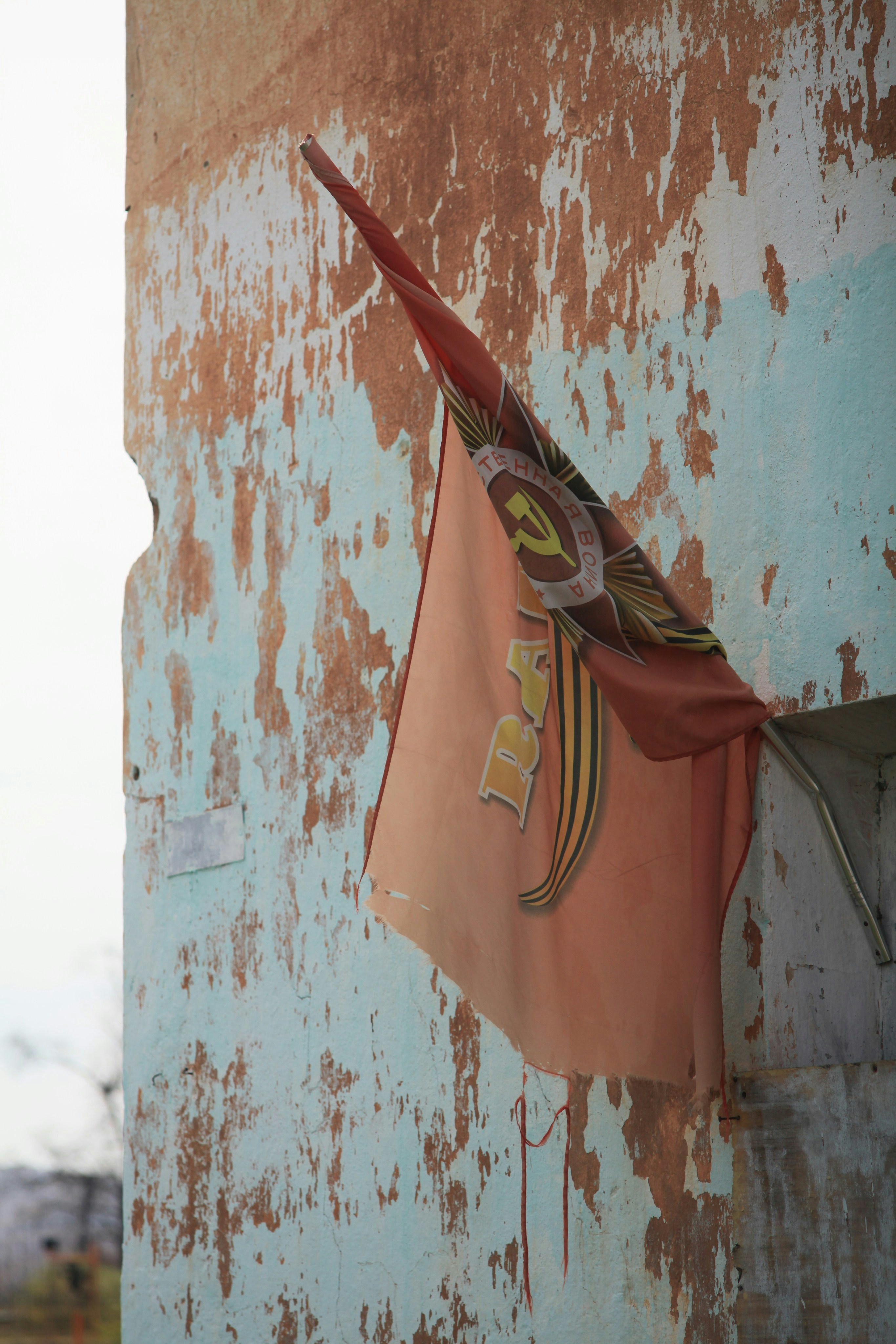 Tattered Flag Clinging to a Sun-bleached Wall