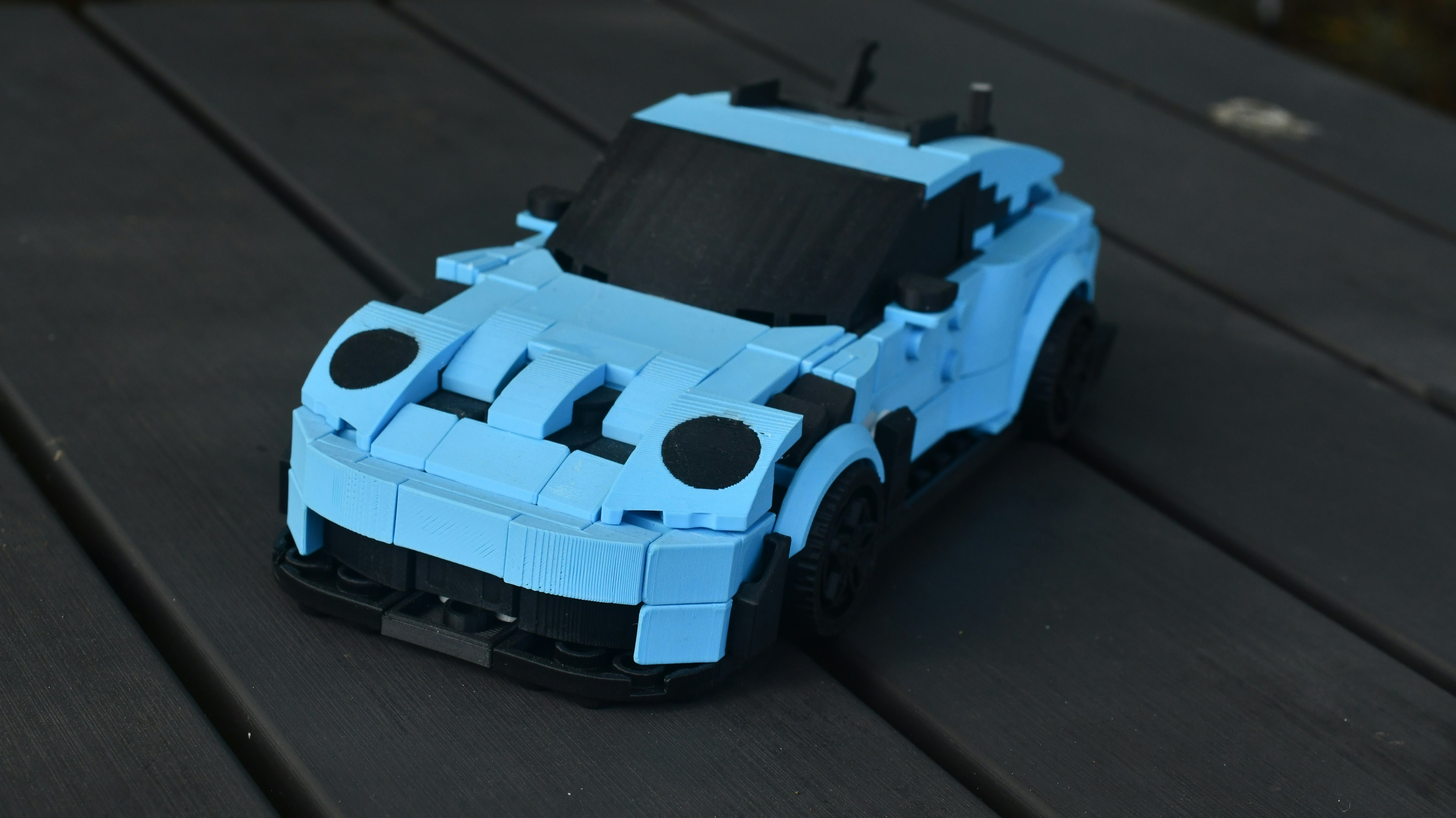 Azure LEGO supercar on a dark wooden dock