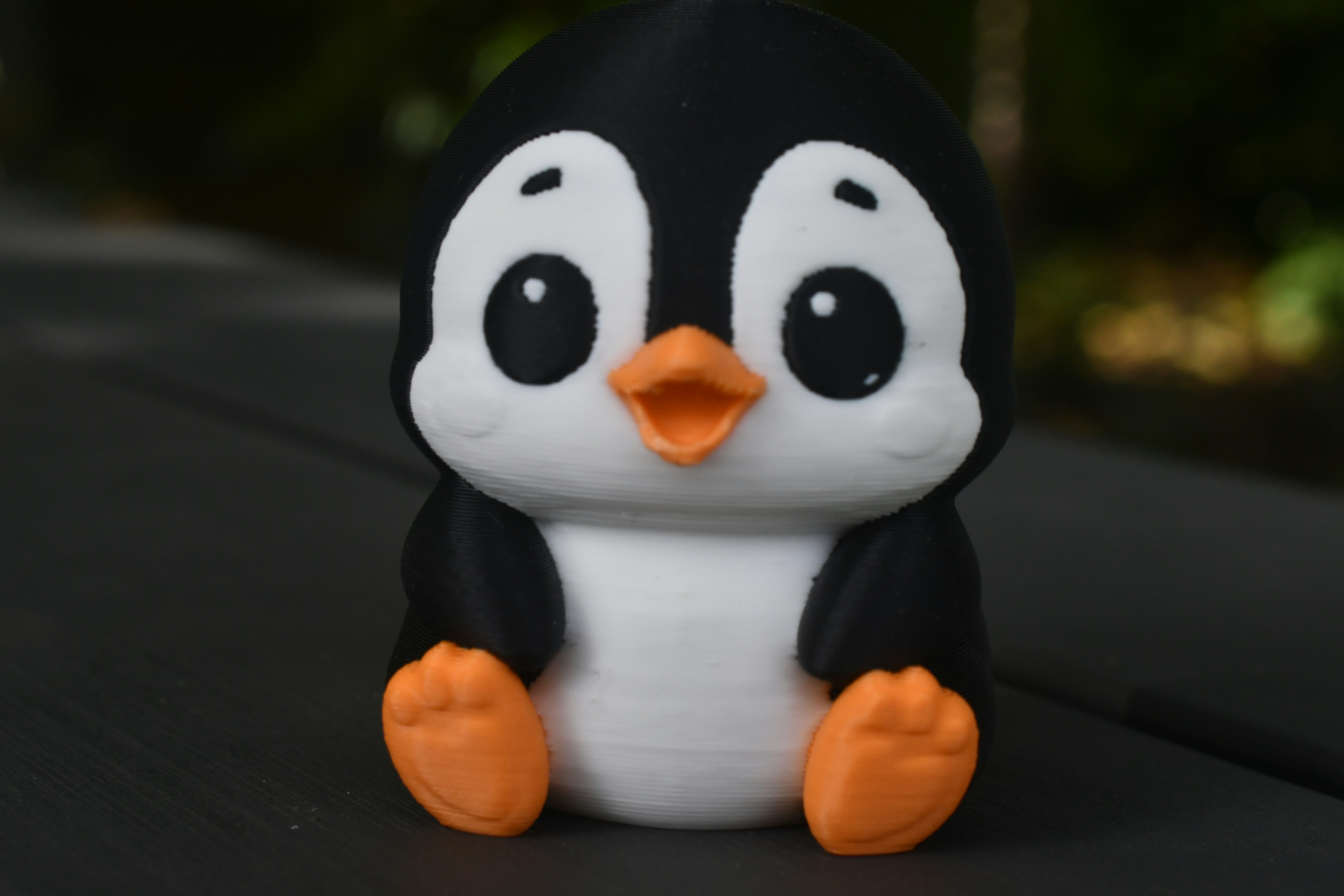 Miniature Penguin Plush Reaching for Play on a Dark Wooden Table