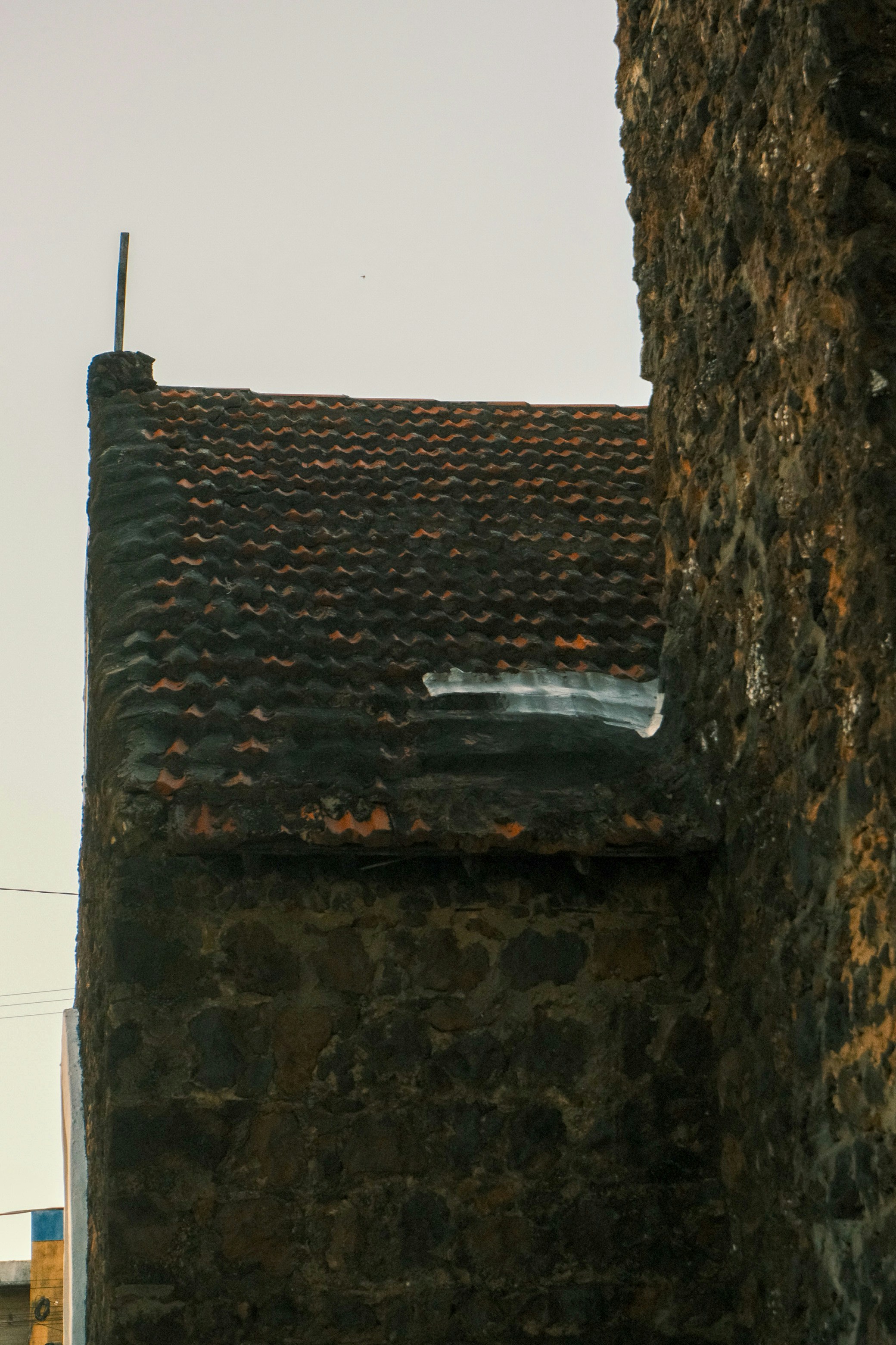 Weathered stone and tiled roof rise along a sunlit alley