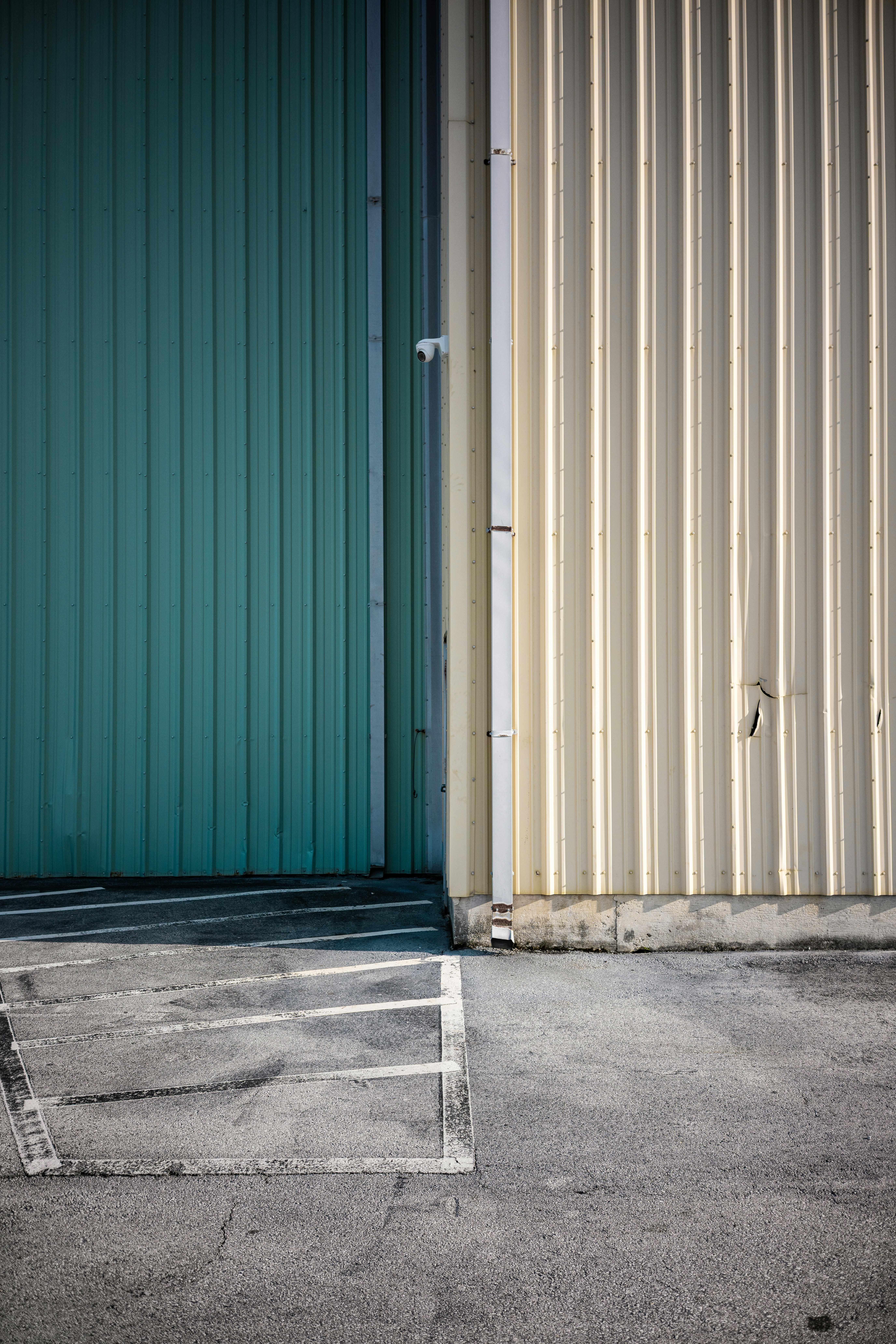 Twin Garage Doors: Teal and Beige Corrugated Facades Meet Asphalt Edge