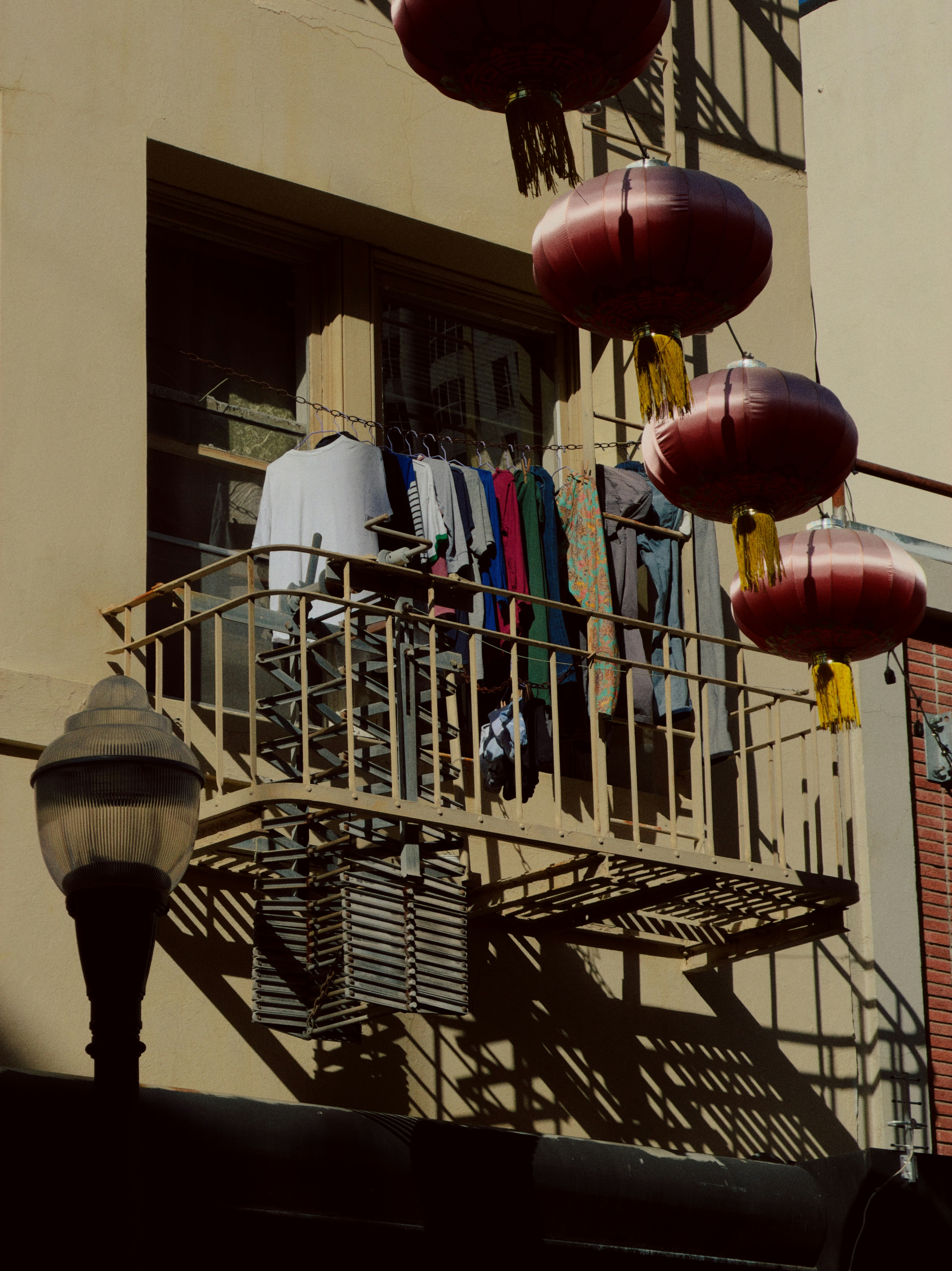 Clothes hanging on a fire escape balcony with red lanterns in the foreground