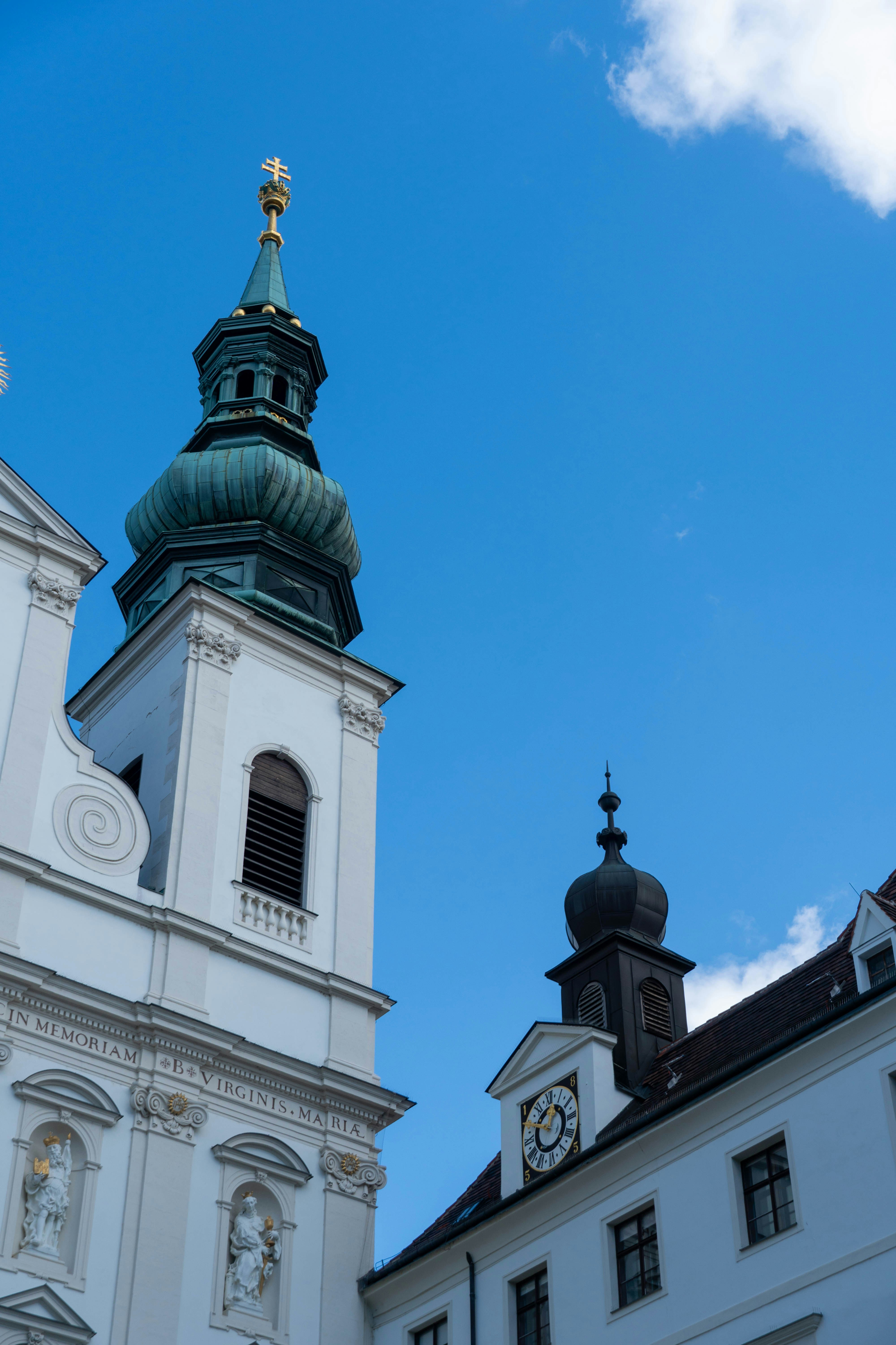 Clocktower Serenade: White facades and teal spires under a clear noon sky