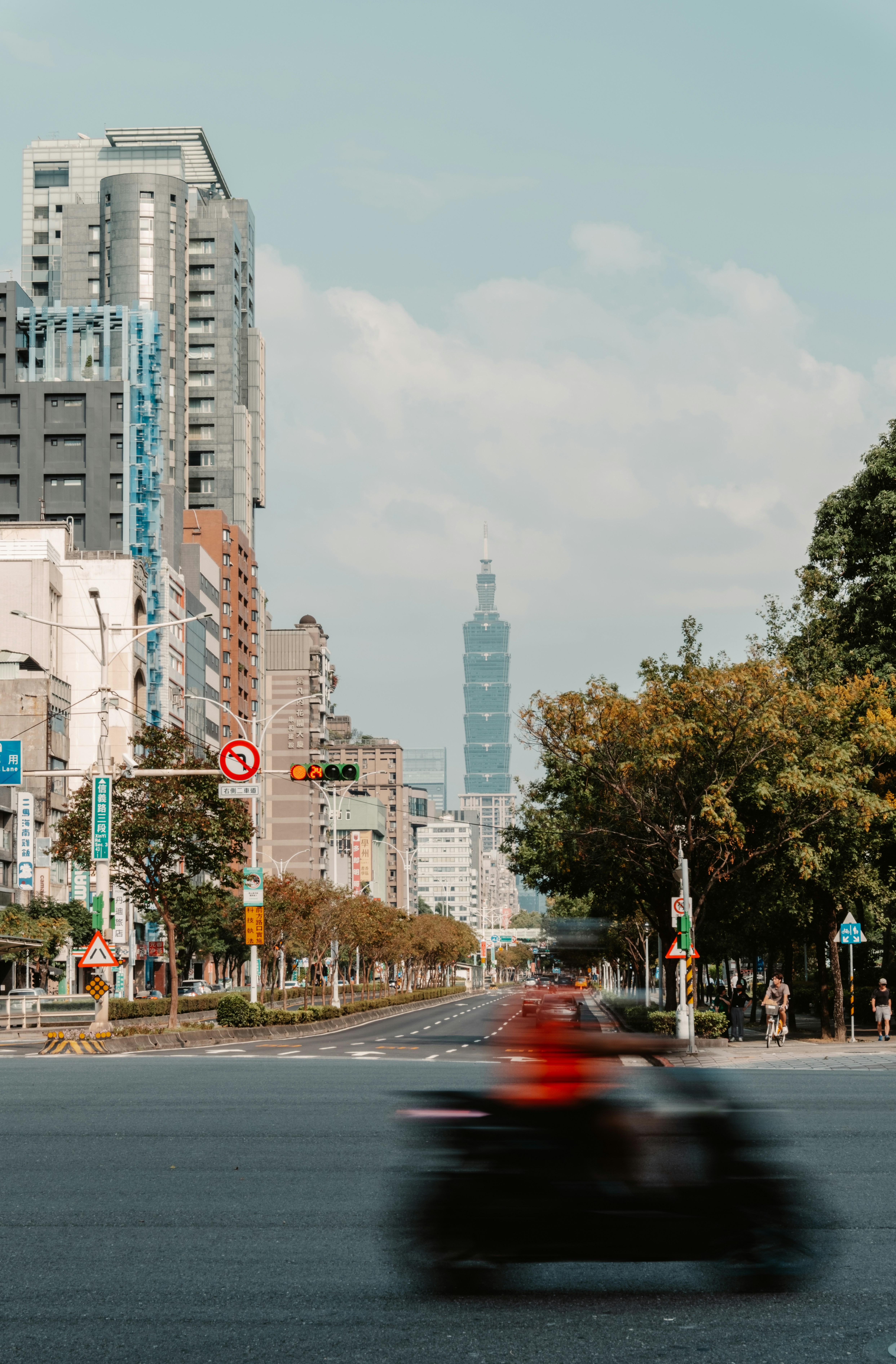 Taipei Boulevard: A Lone Scooter in Motion Under Towering Skies