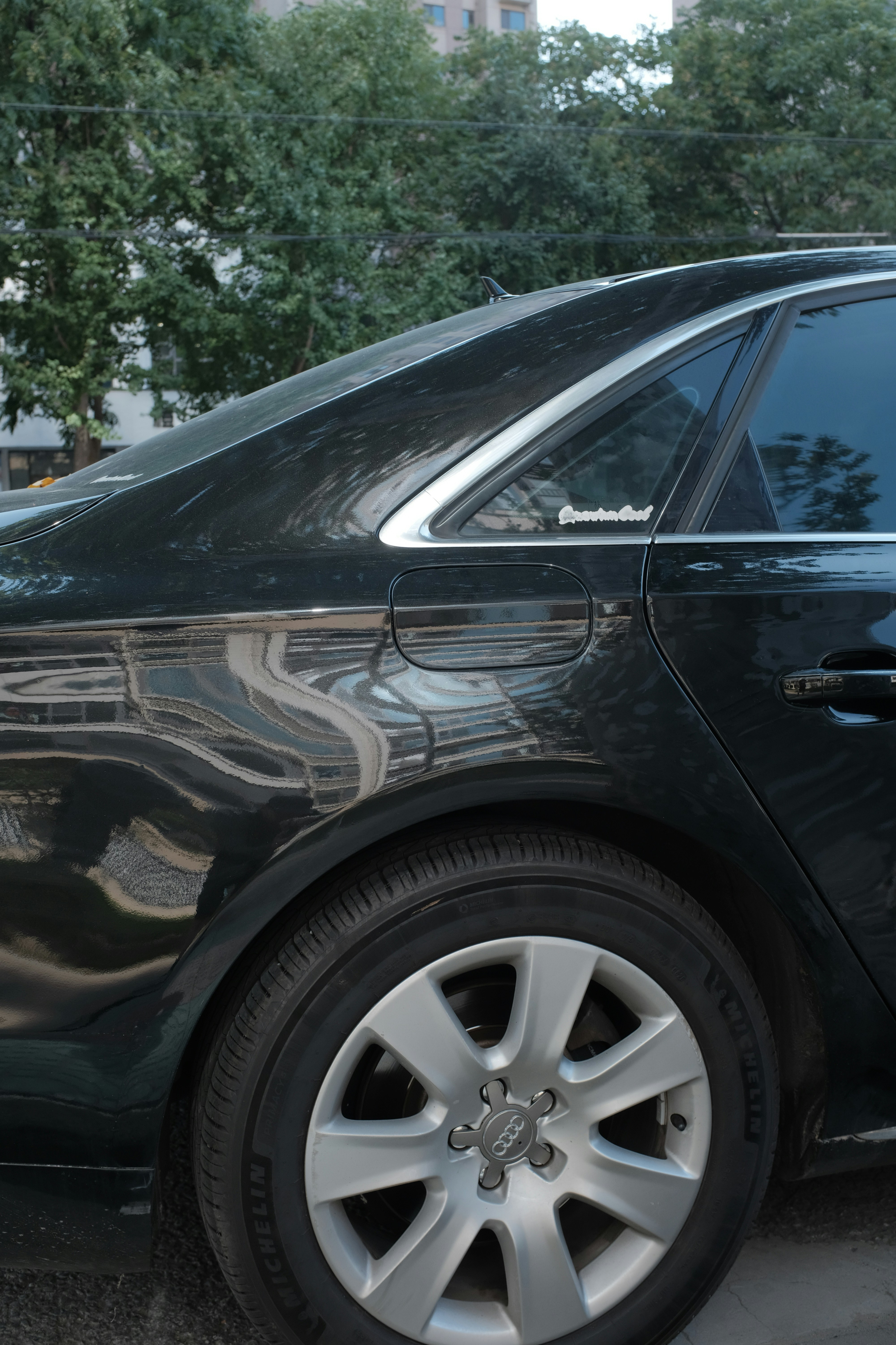 Rear Quarter of a Dark sedan: Curved lines and chrome highlight